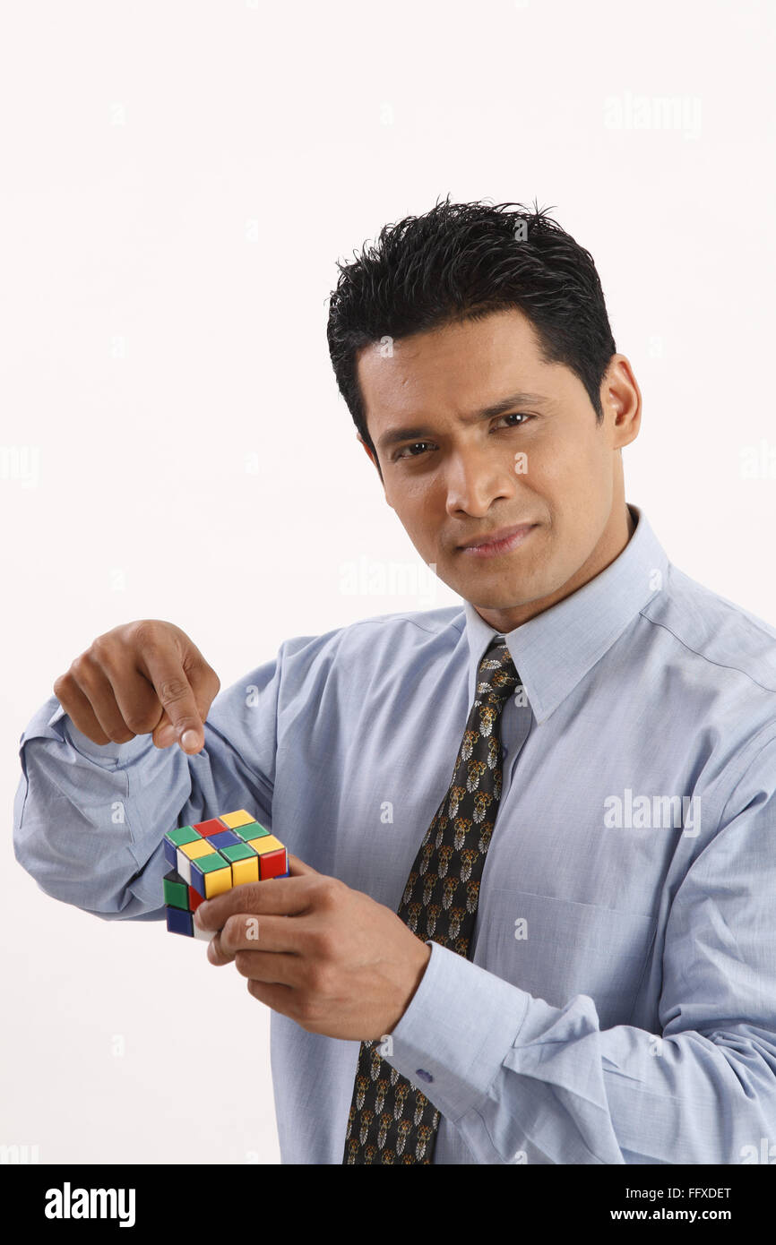 Businessman holding Rubik cube in one hand and pointing index finger MR ...