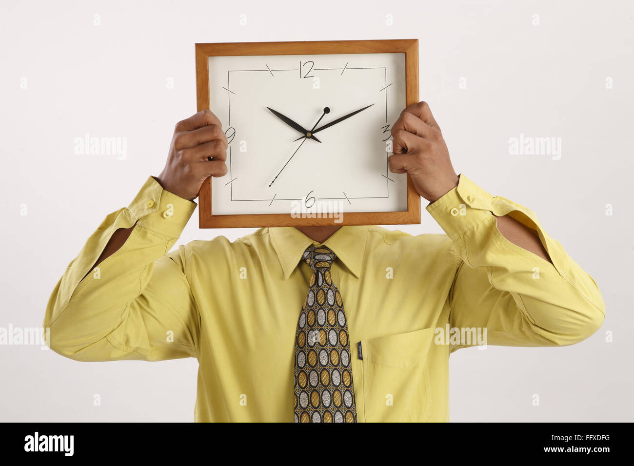 Businessman holding wall clock in both hands over his face and hiding ...