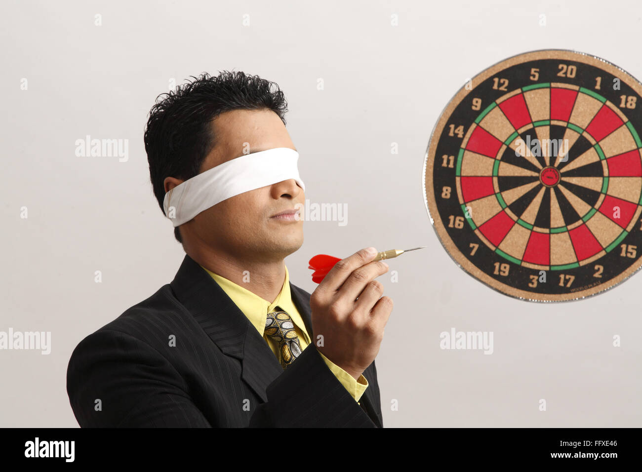Businessman holding dart in one hand and dart board on wall aiming with ...