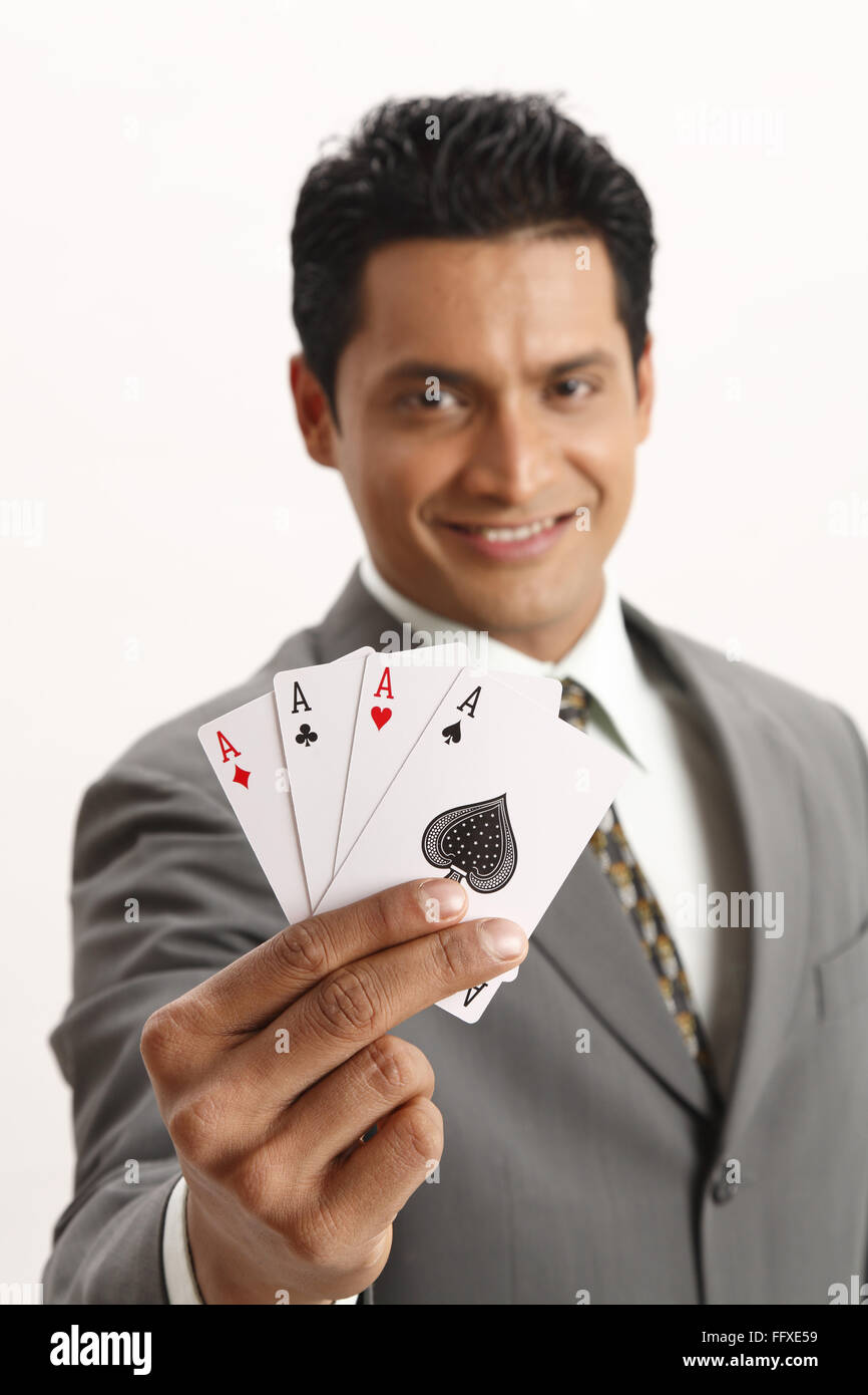 Businessman holding four aces of playing cards in his thumb index and ...