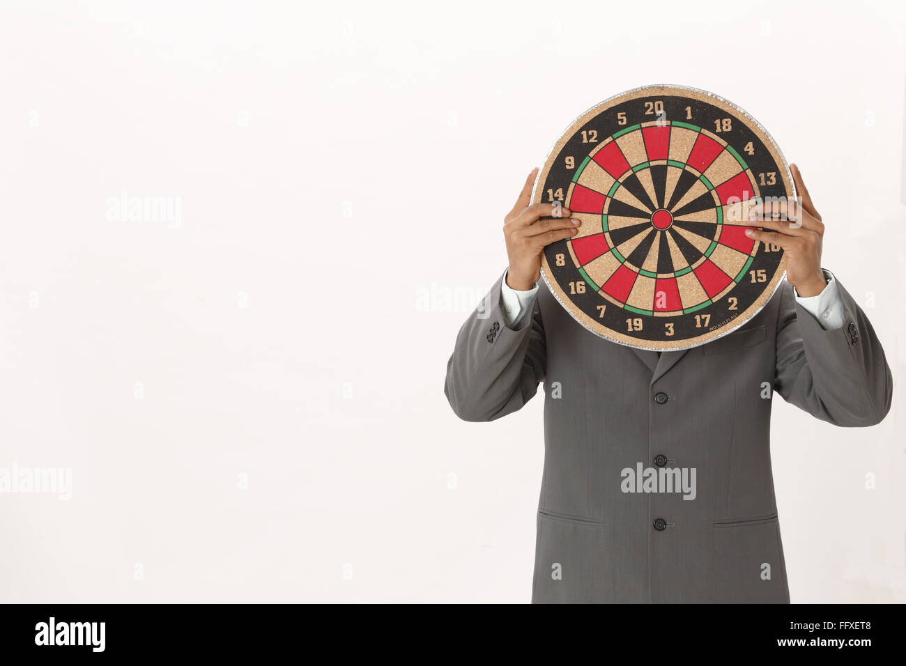 Businessman holding dart board in front of his face in both hands MR ...