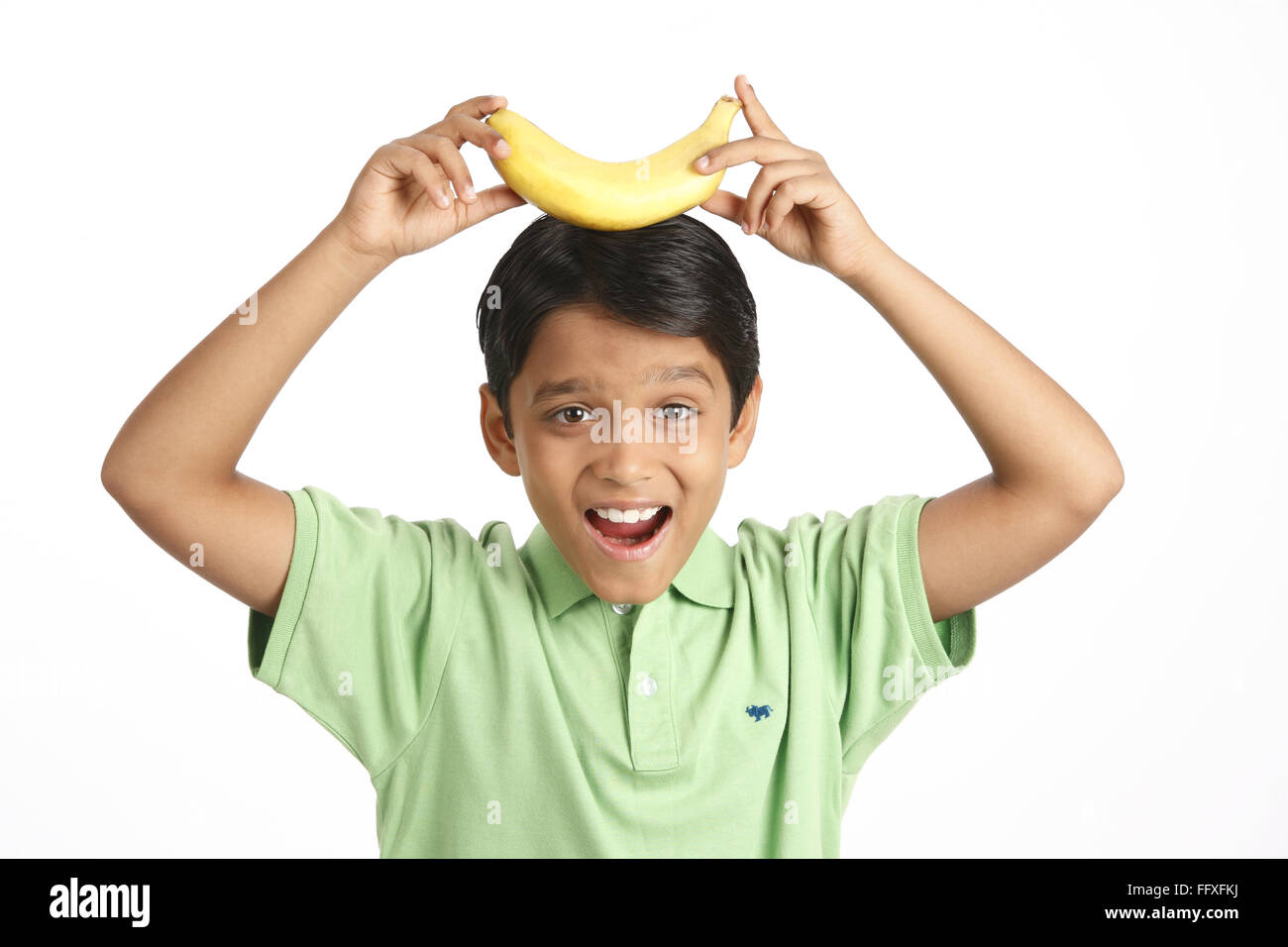 Ten year old boy kept yellow banana on head holding with both hand ...