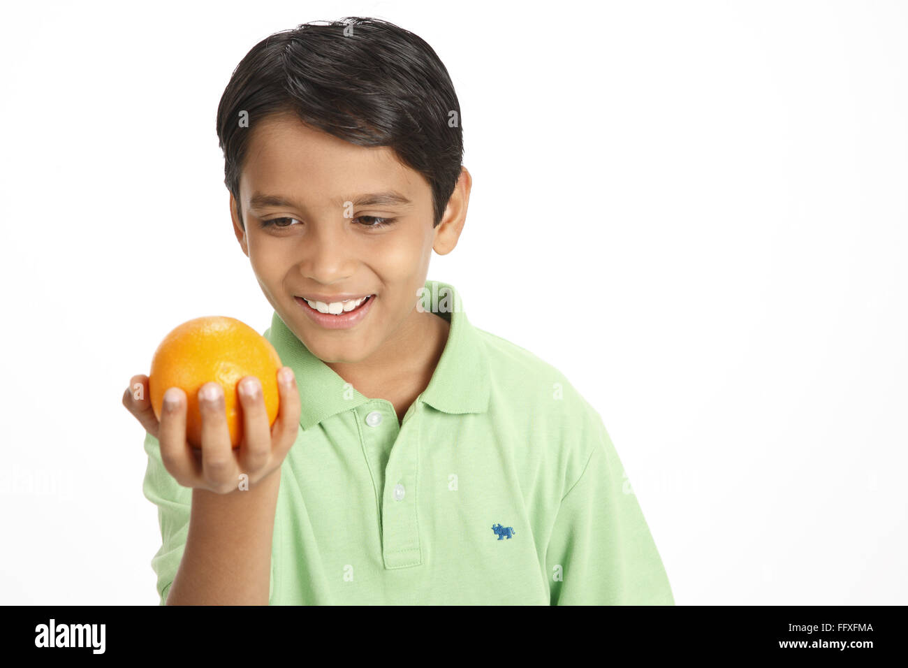 Ten year old boy holding orange in one hand and looking at it MR#703V ...