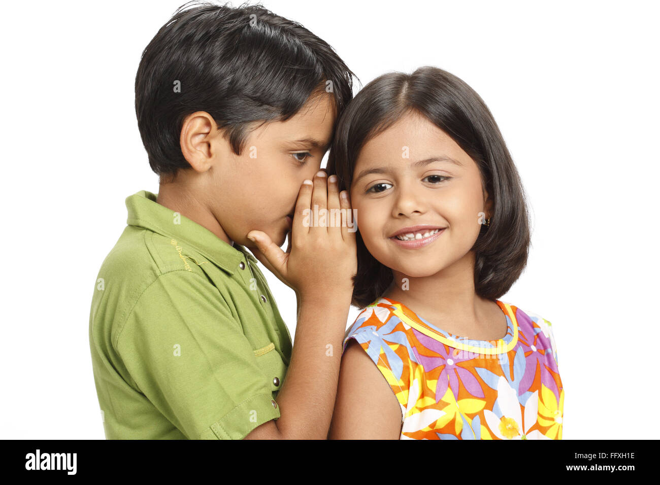 Ten year old boy whispering something in eight year old girl's ear MR ...