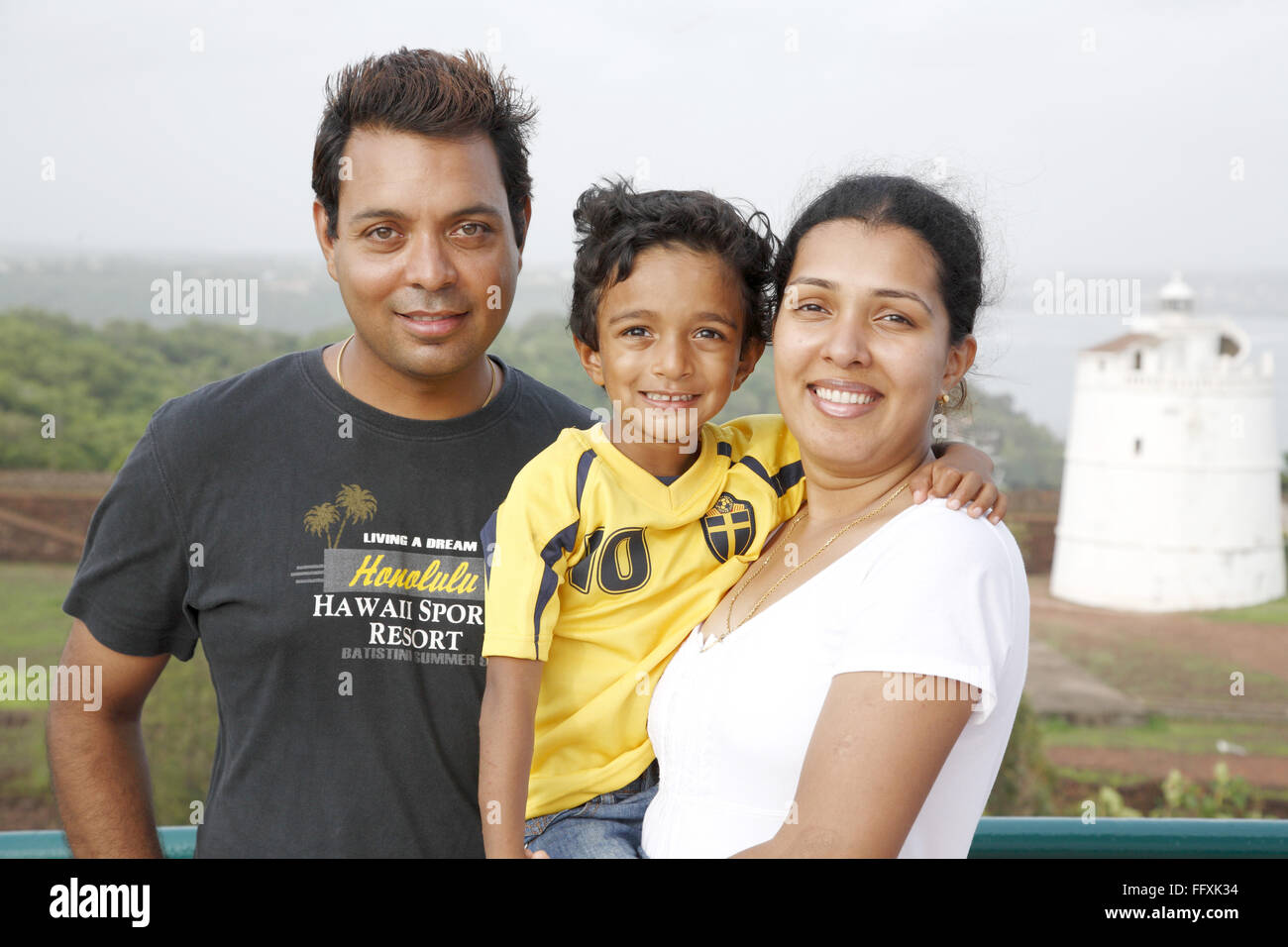 Parents and son , Lighthouse of Fort Aguada in background , Goa , India ...