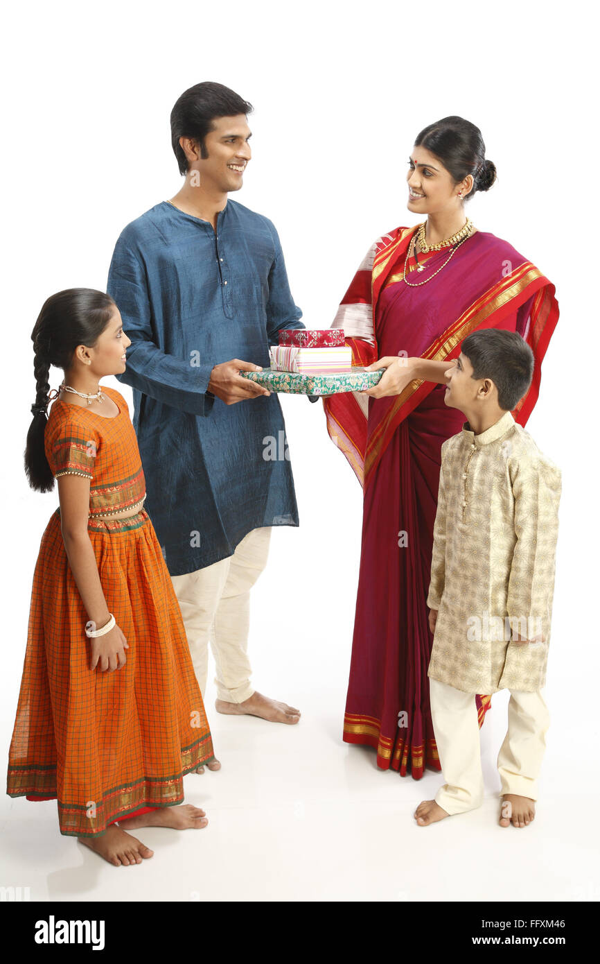 Rich rural farmer giving gift boxes to wife children standing with them ...