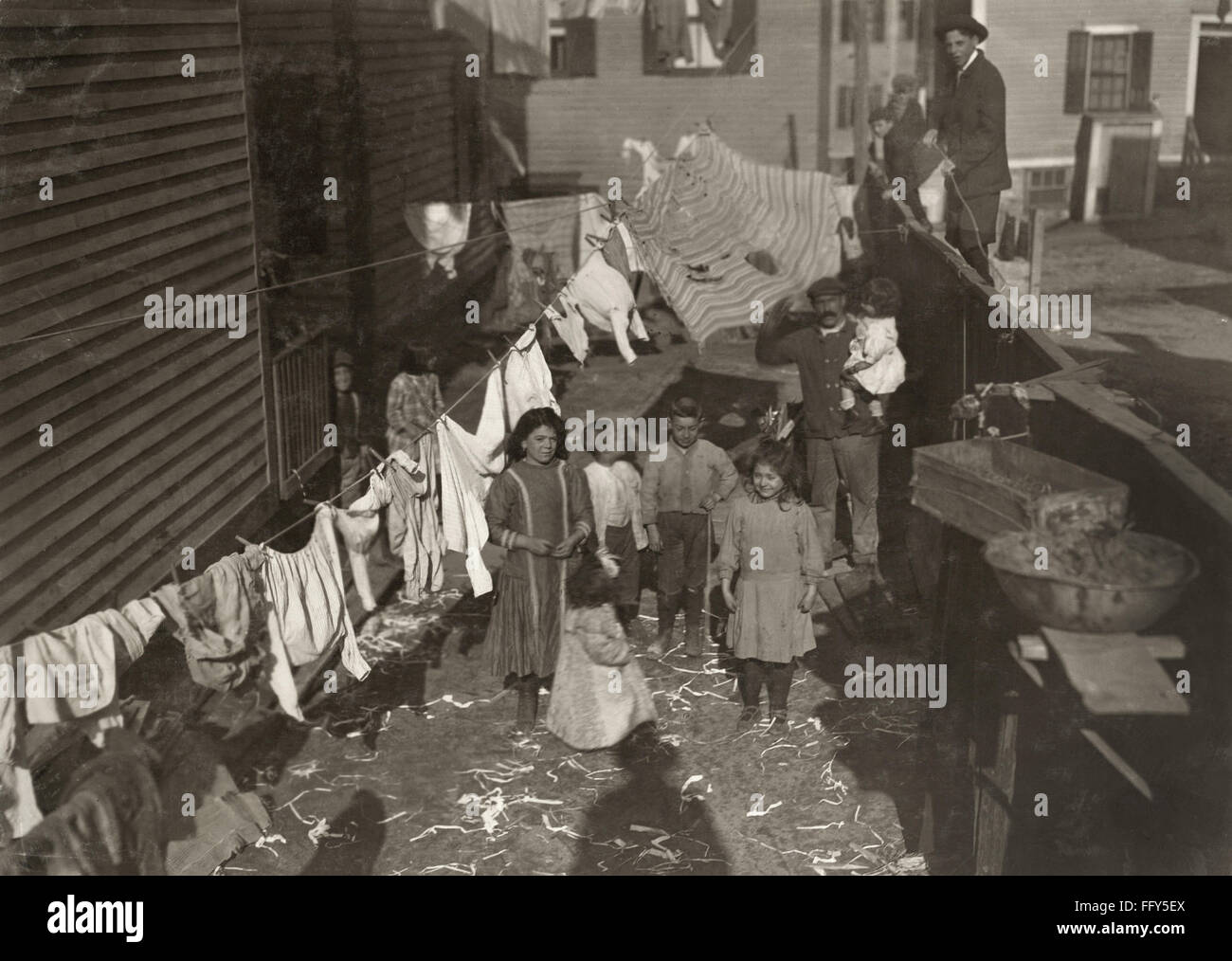 HINE: MILL HOUSING, 1912. /nTextile mill worker's family in the yard with a clothesline covered ...