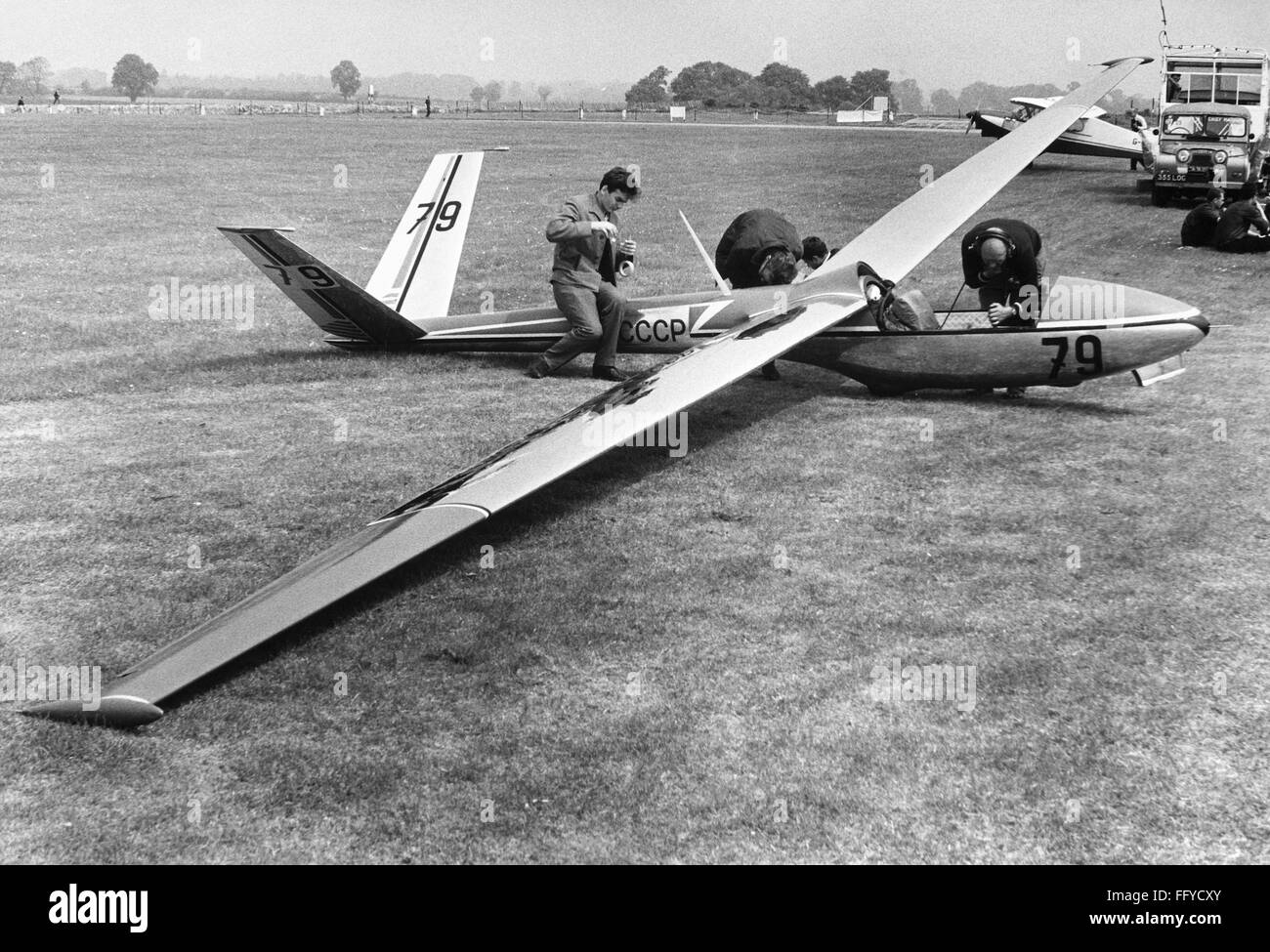 GLIDER COMPETITION. /nFour men working on a single-seat glider at a ...