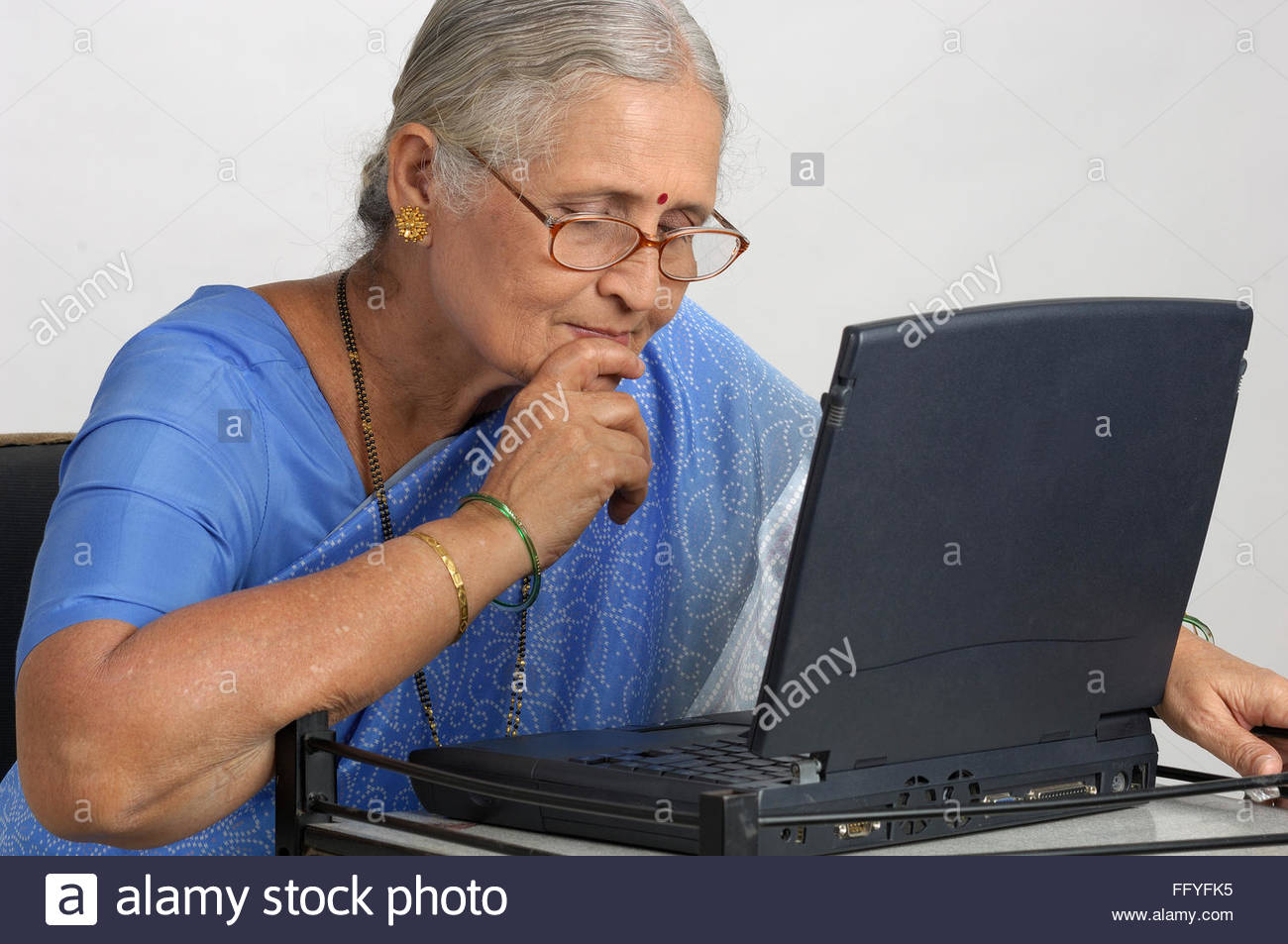 South Asian Indian old lady looking at laptop screen reading E mail ...
