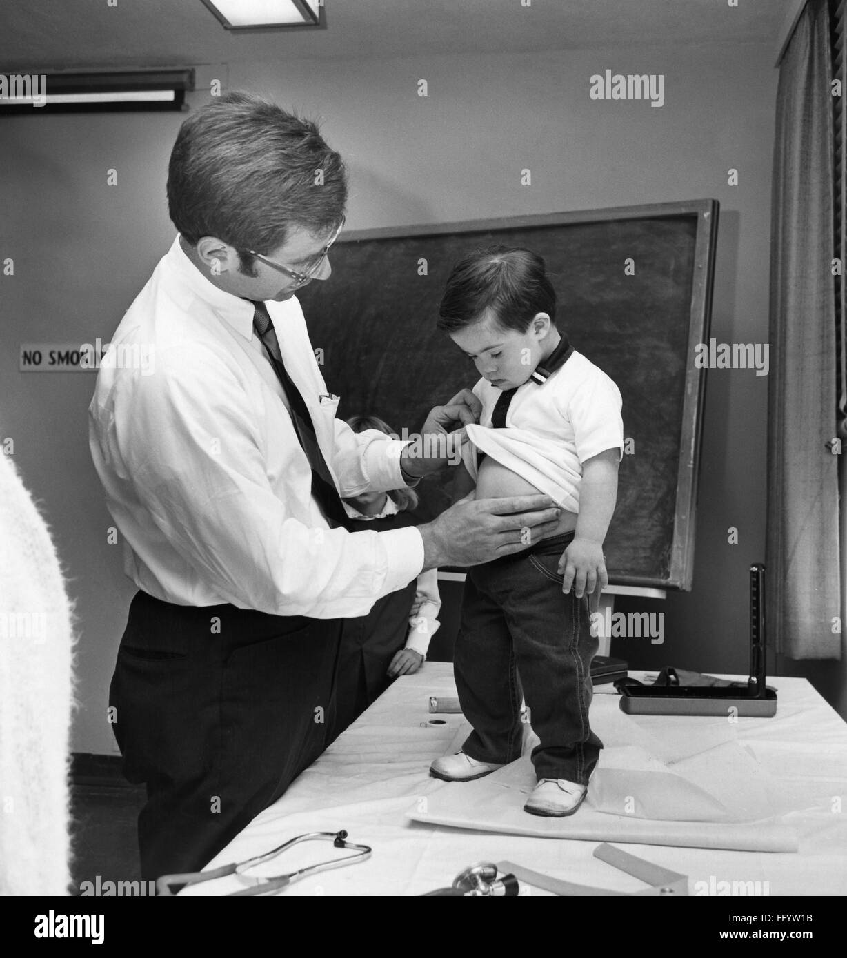 DOCTOR AND PATIENT, c1965. /nA doctor examining a young boy with Down ...