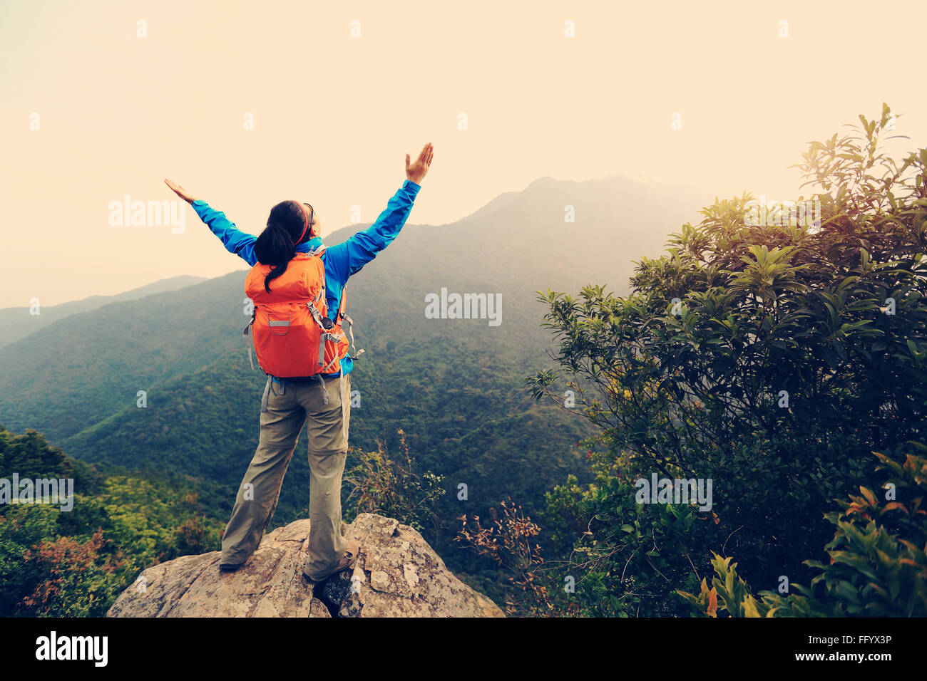 cheering young woman hiker open arms on mountain peak Stock Photo - Alamy