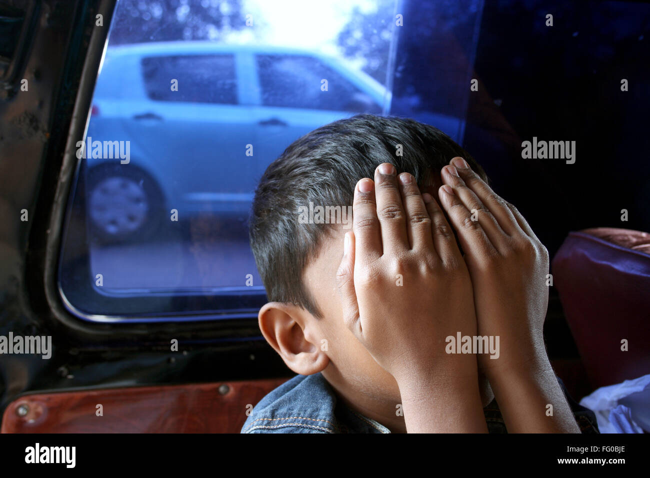 A boy covering face with hands Stock Photo - Alamy