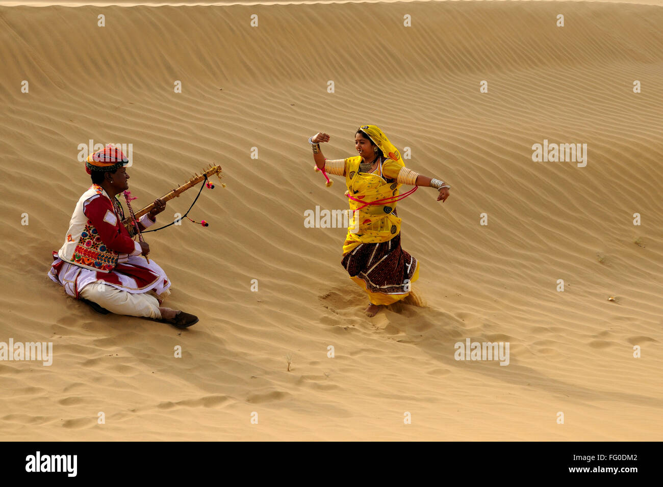 Couple playing folk music and dancing in desert sand dunes Jaisalmer ...