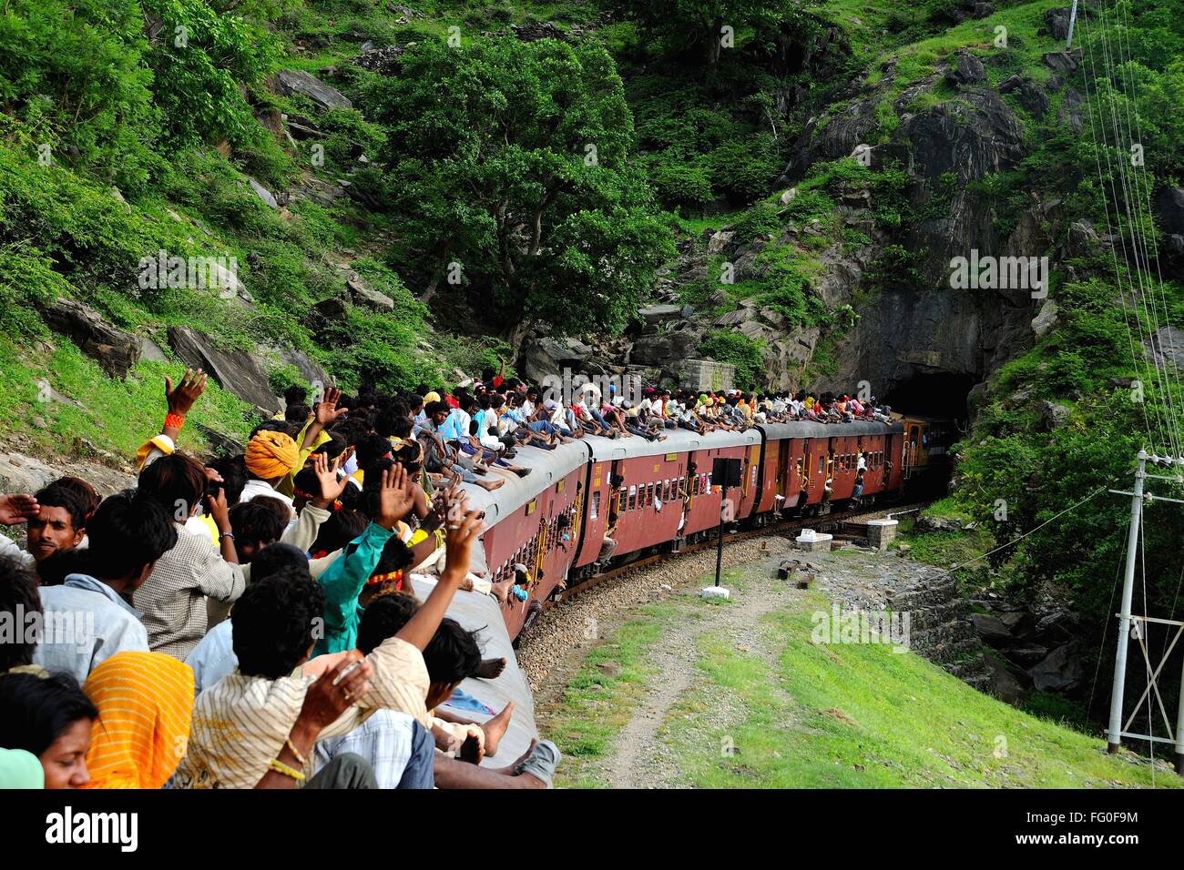 Commuters sitting on roof of train at tunnel ; Kamali Ghat ; Rajasthan ...