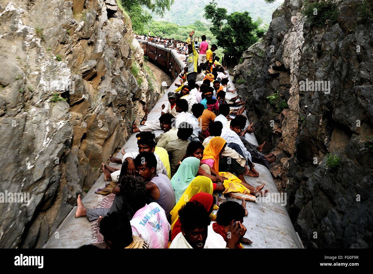 Commuters sitting on roof of train going through cliff ; Kamali Ghat ...