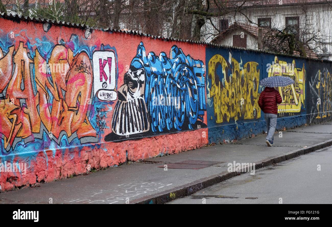 Slovenia - Ljubljana - Passant runs along a wall with graffiti Stock ...