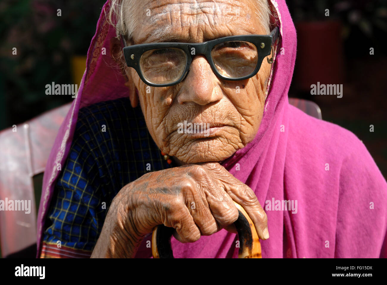 Rural old woman resting herself holding stick with one hand , Lonavala ...