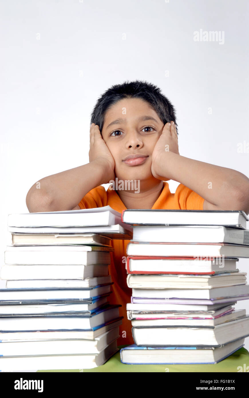 Boy thinking kept both hand palm on cheek standing with stack of books ...