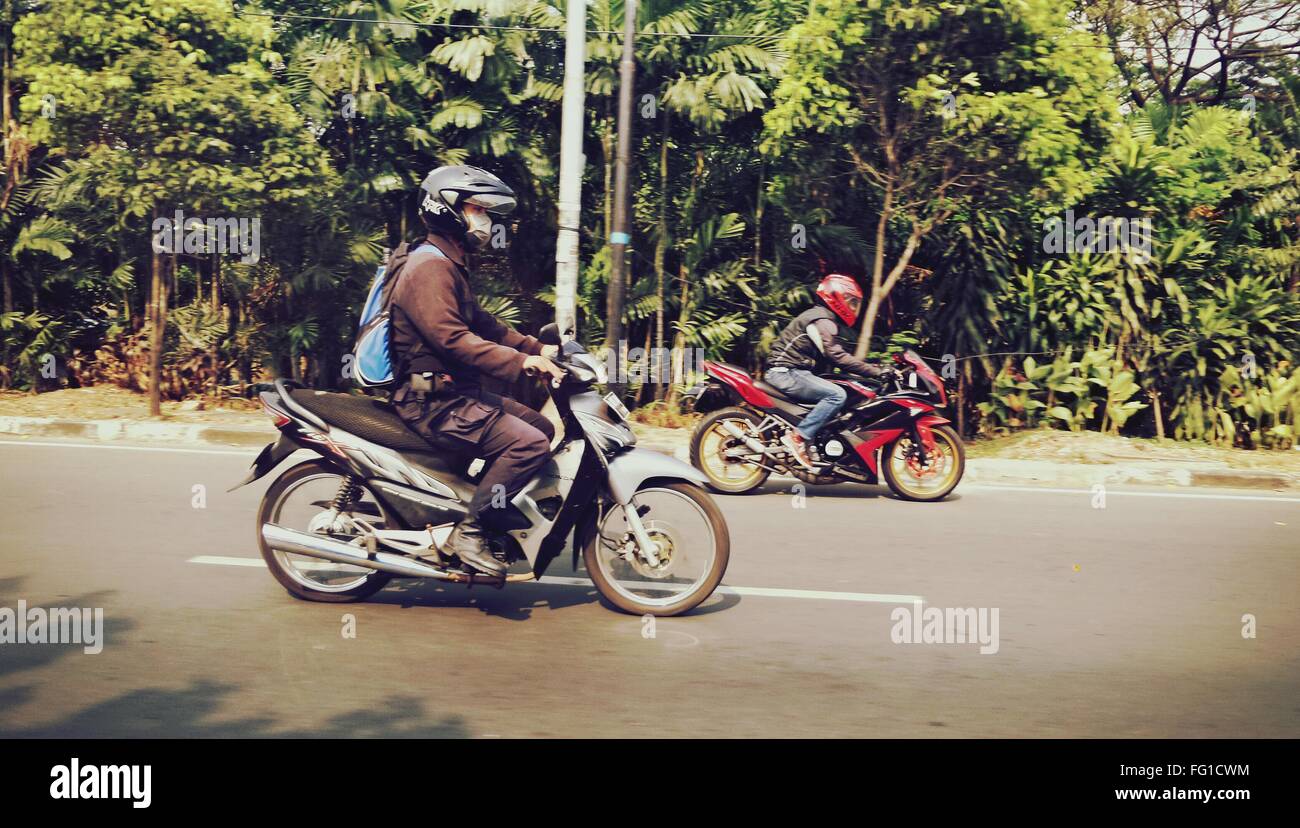 People Riding Motorcycle On Road Against Trees Stock Photo - Alamy