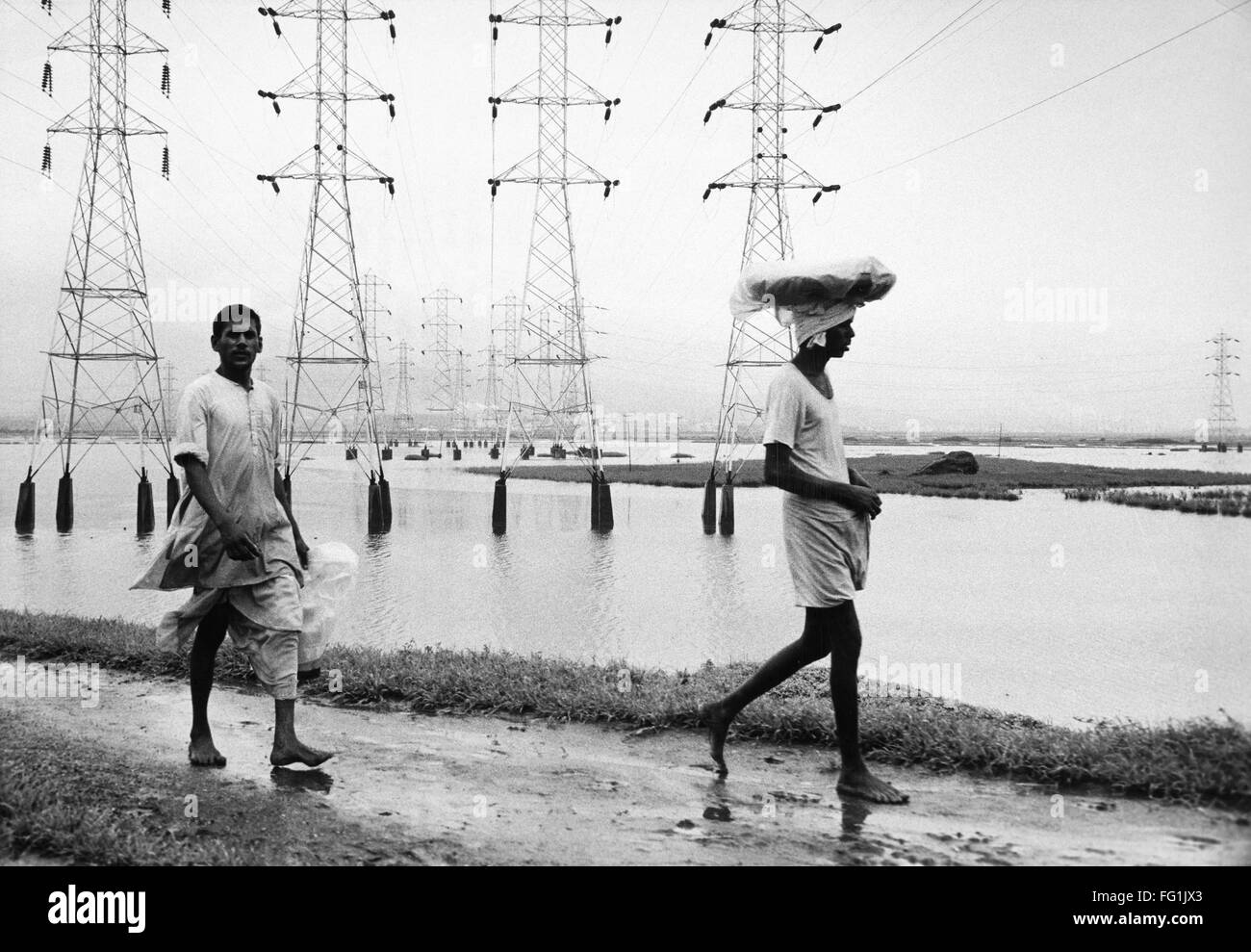 INDIA: POWER LINES, 1967. /nTwo men walking on a dirt road near Bombay ...