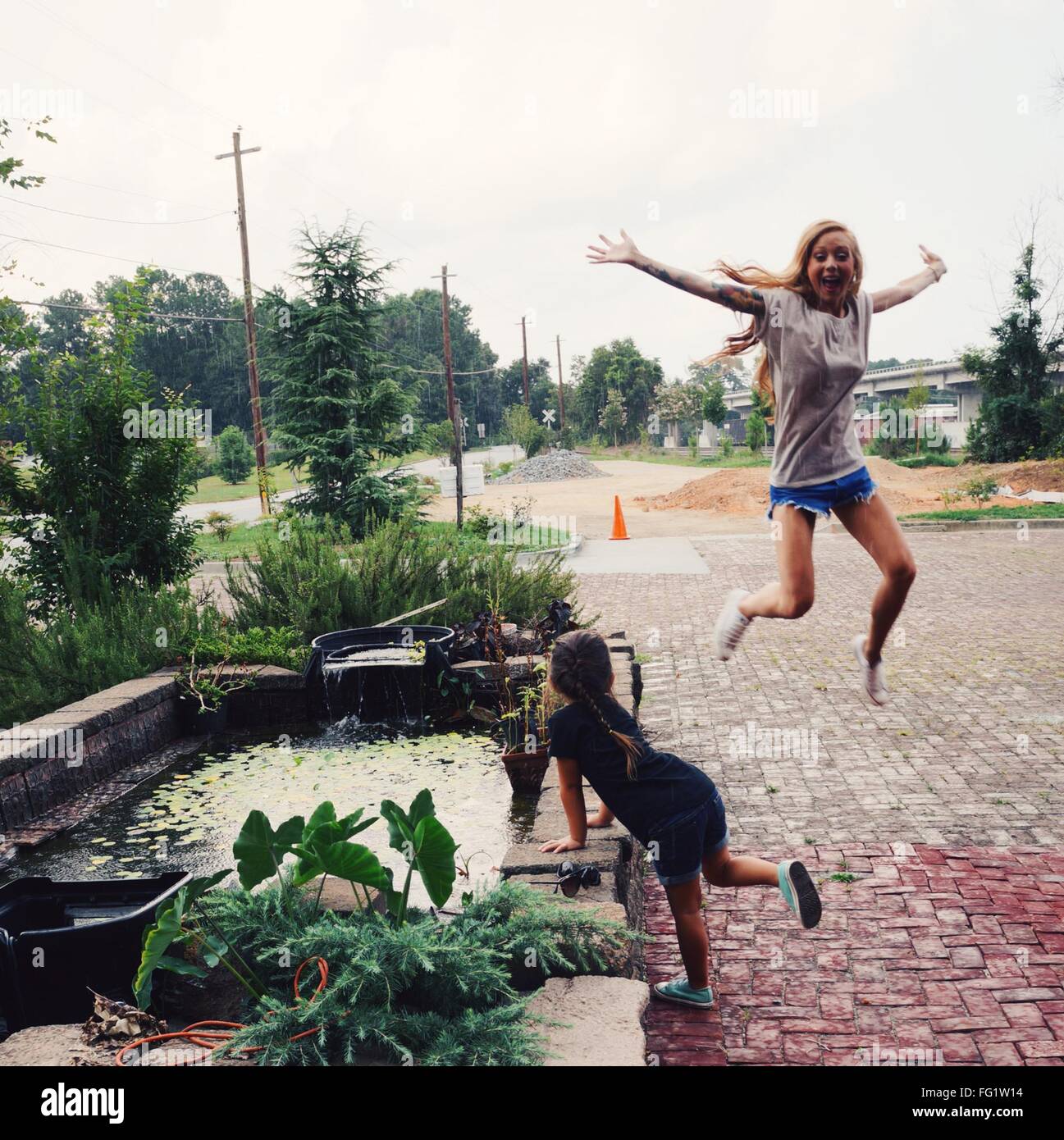 Full Length Of Playful Girls By Pond Against Sky Stock Photo - Alamy