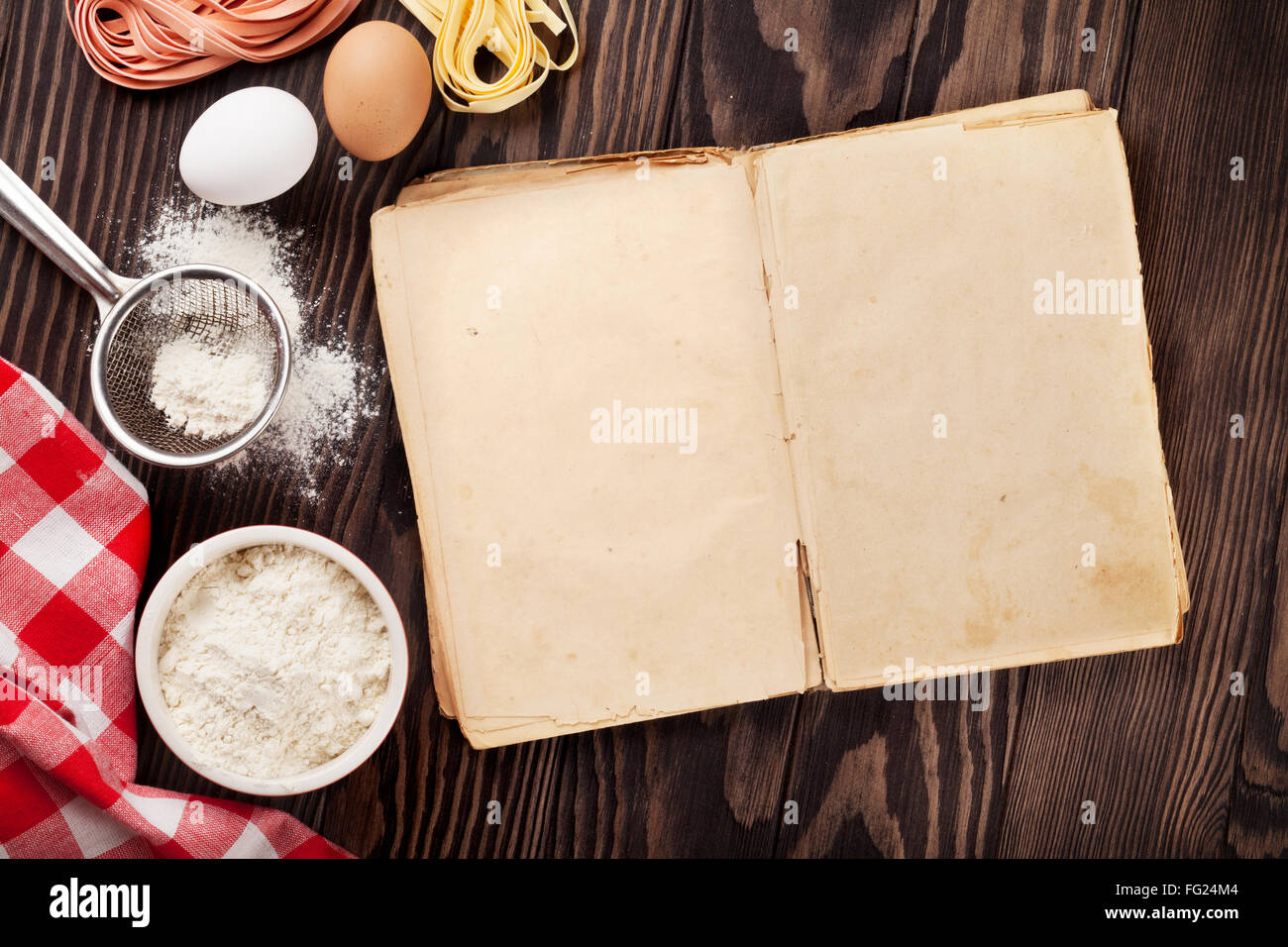 Homemade pasta cooking and vintage cooking book on wooden table. Top ...