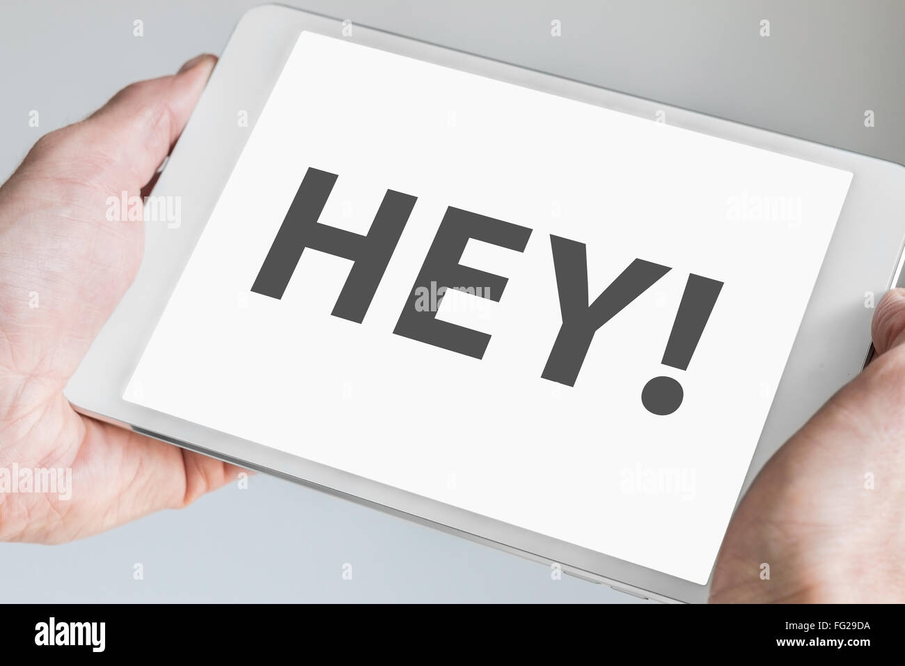Hey text displayed on touch screen of a modern tablet computer. Hands ...