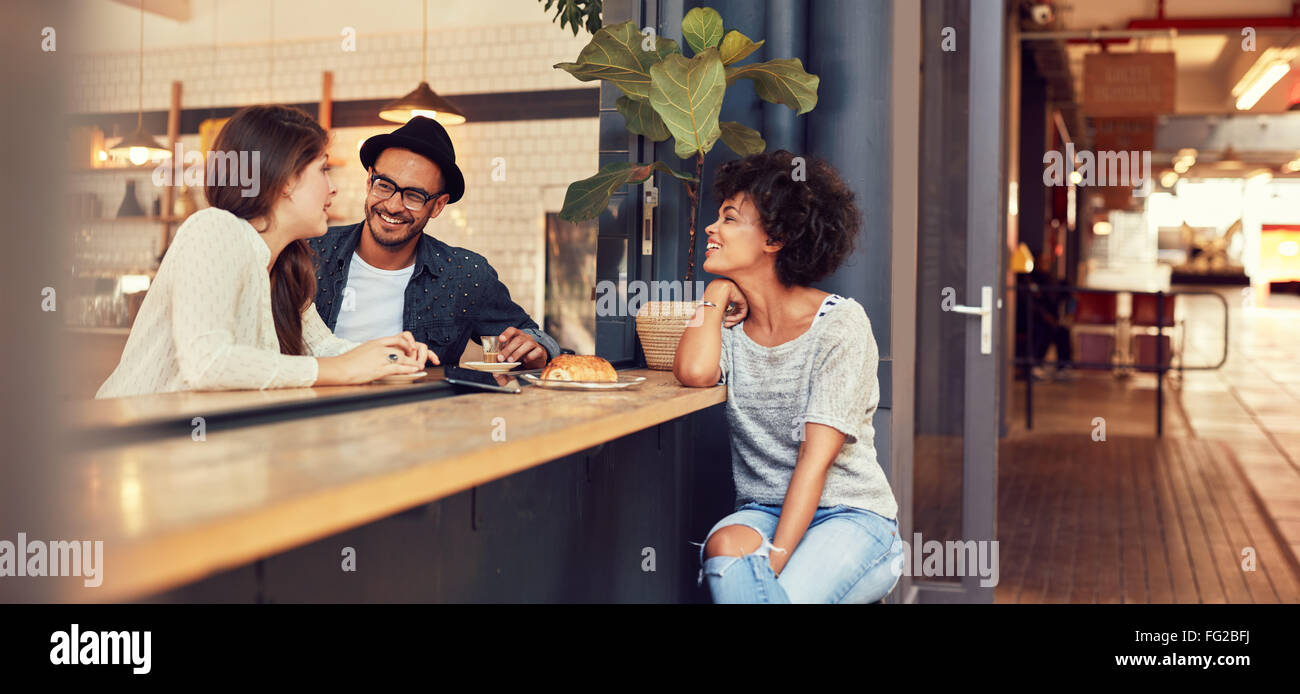 Portrait of three young people sitting together at a cafe. Group of ...
