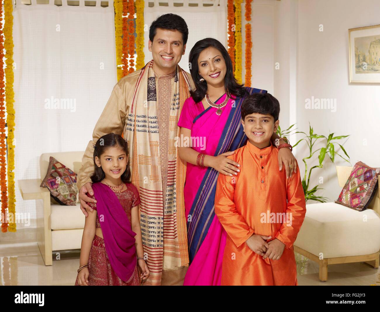 Indian parents with children in traditional dress standing in house ...