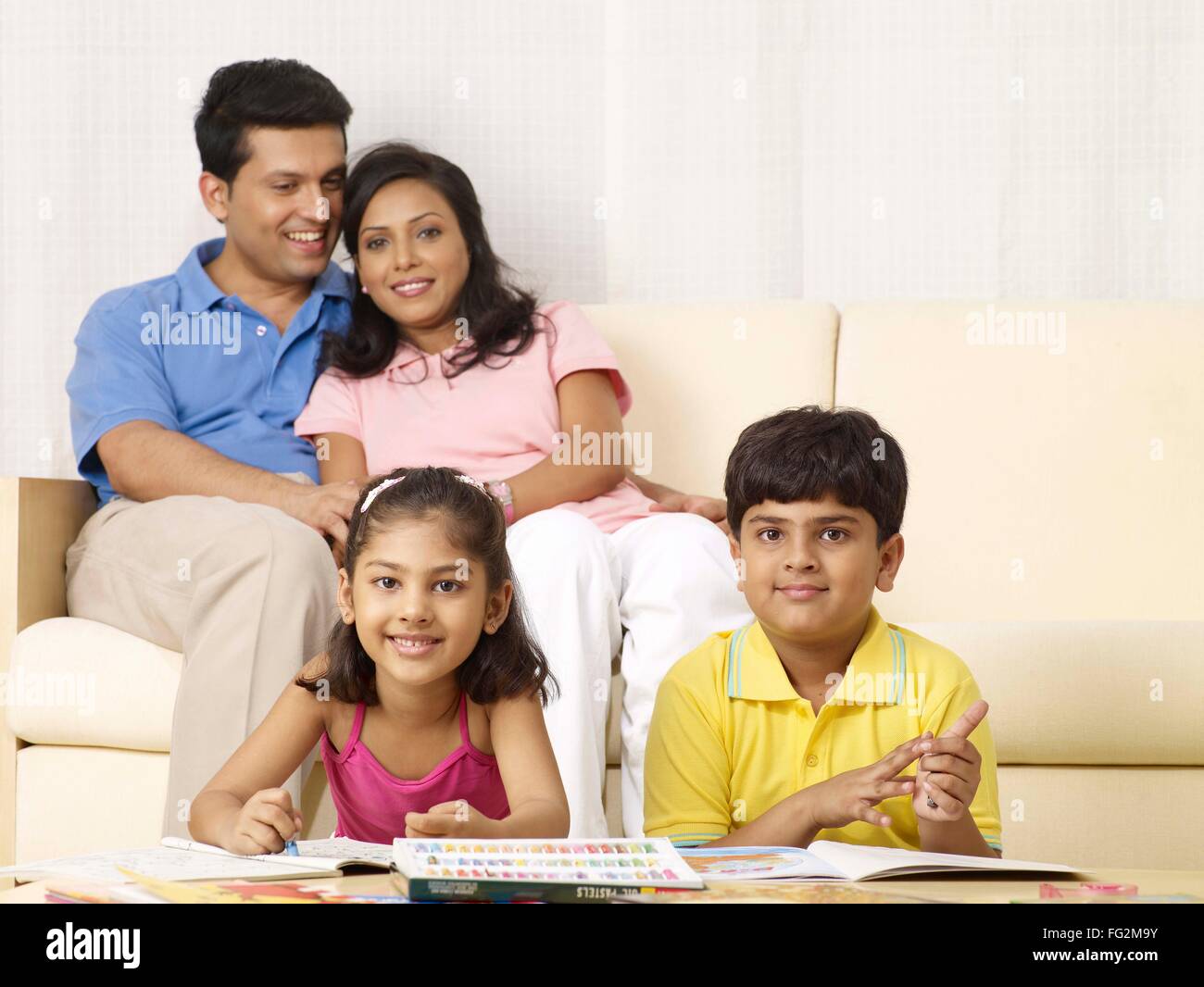 Children doing drawing work parents sitting behind them in house MR ...