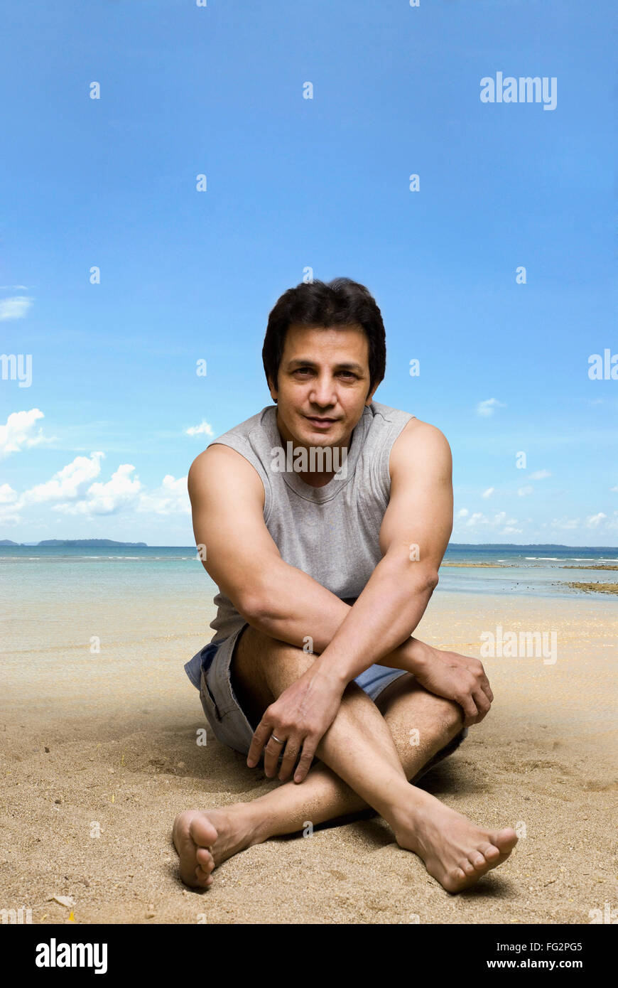 Man sitting on sand at seashore MR#779G Stock Photo - Alamy