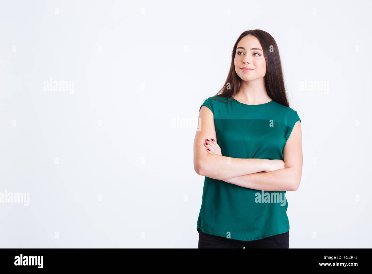 Attractive pensive young woman standing with hands folded over white ...