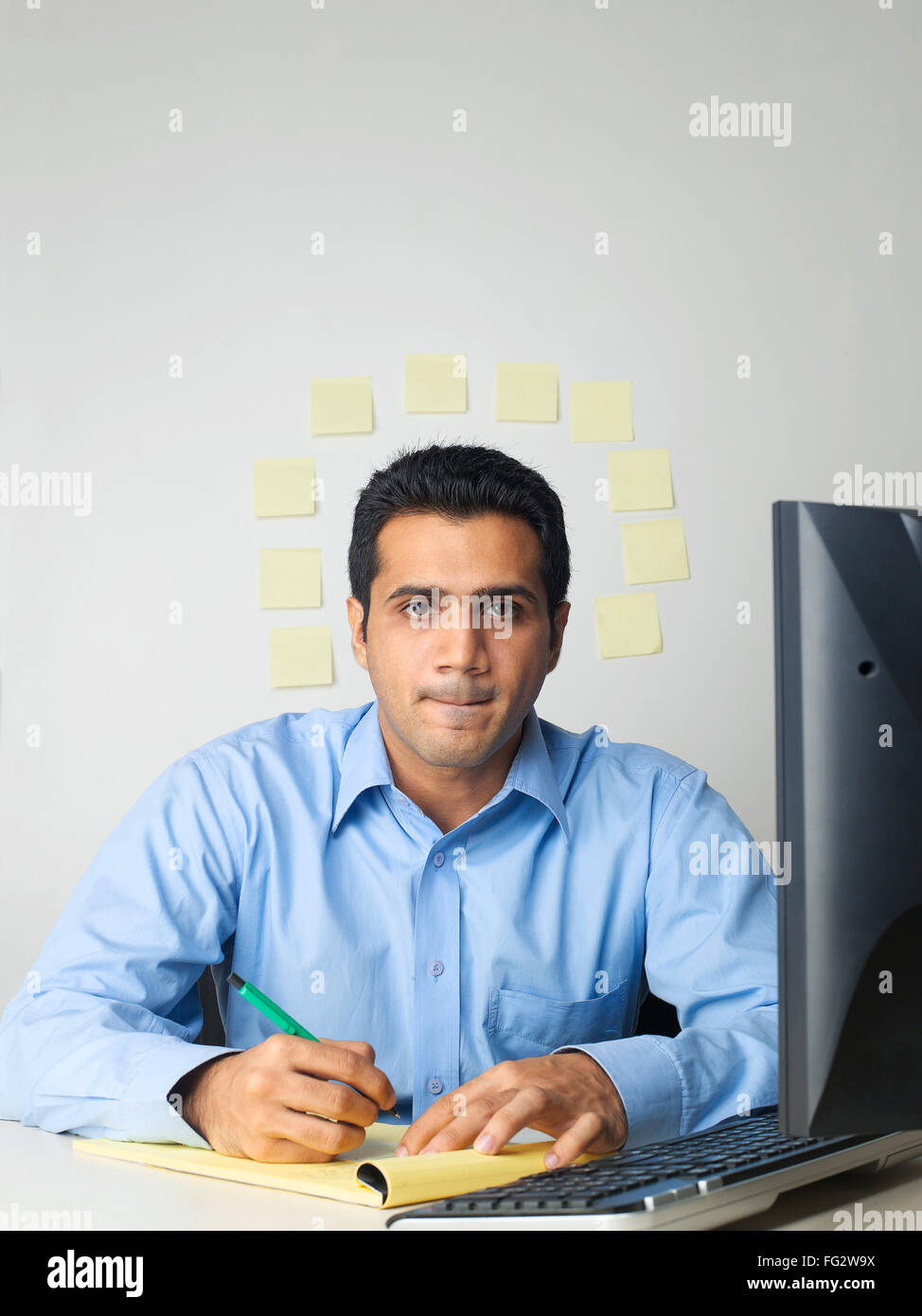 Executive writing on notepad sticky notes on wall in background MR#779K ...