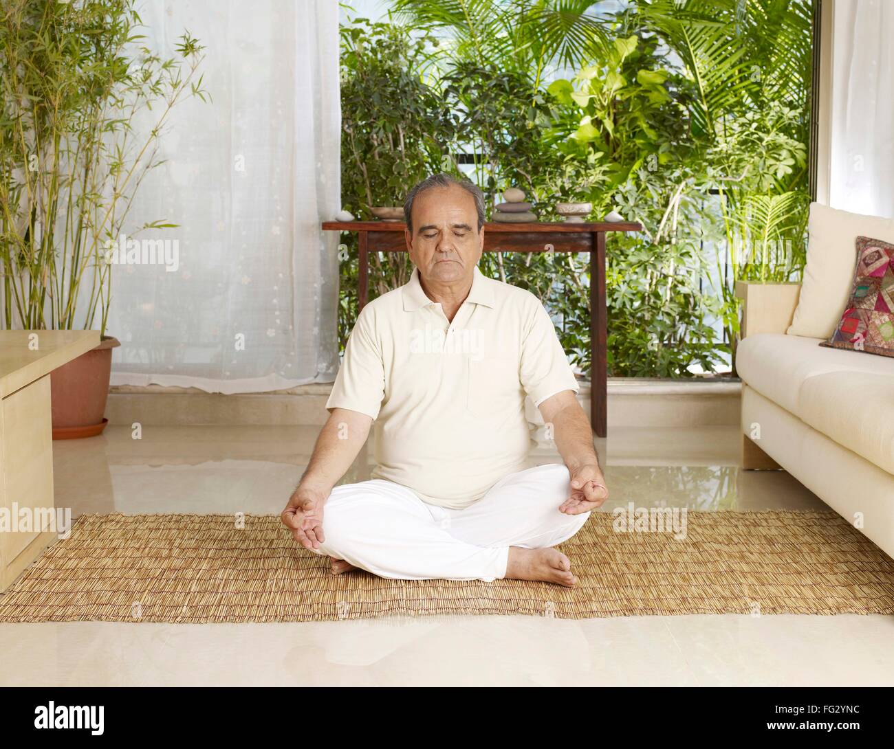 Old man closed eyes doing yoga sitting in padmasan posture on mat MR ...