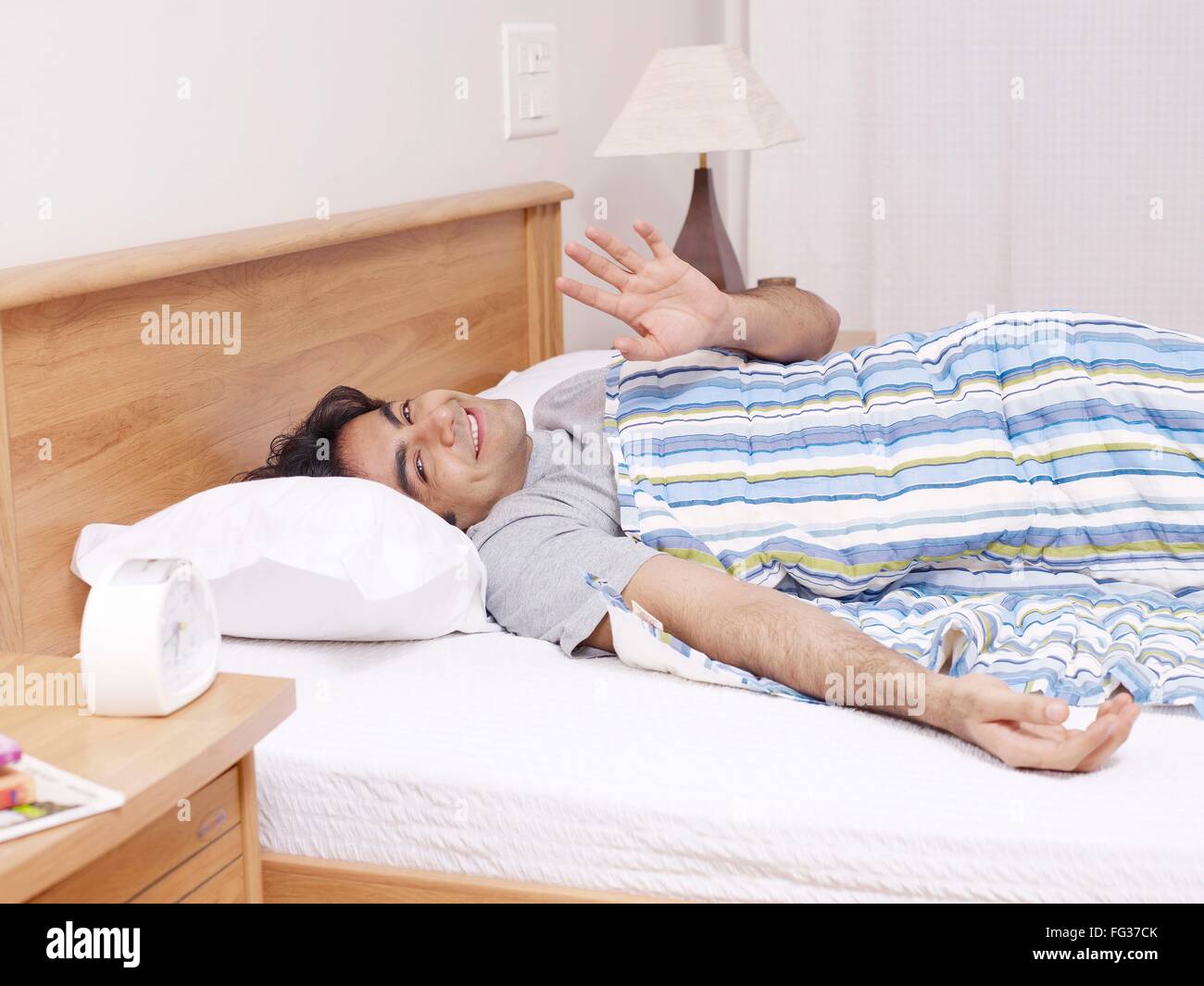 Young man showing hand laying on bed MR#702V Stock Photo - Alamy