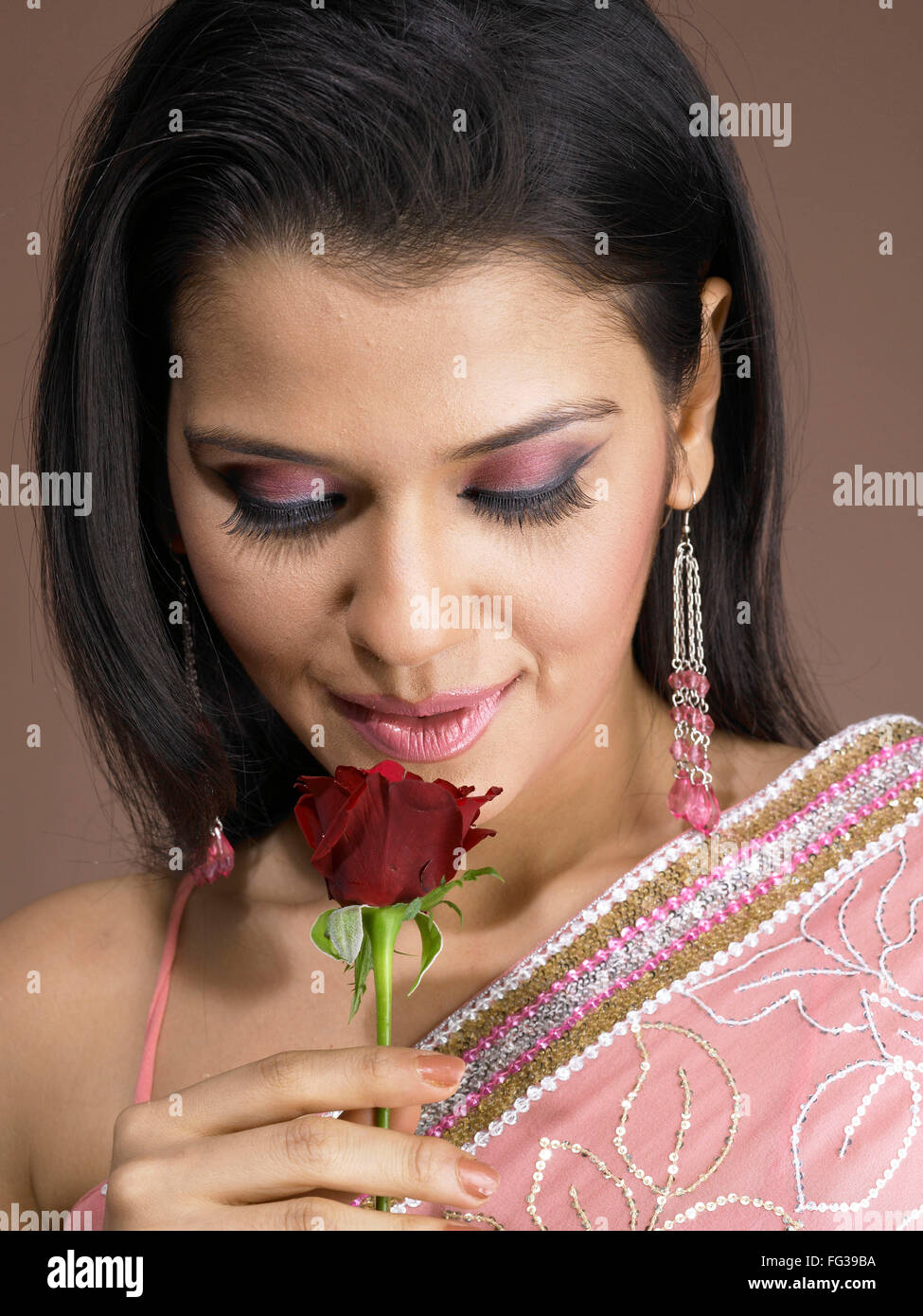 South Asian Indian woman smiling and smelling red rose flower MR # 702 ...