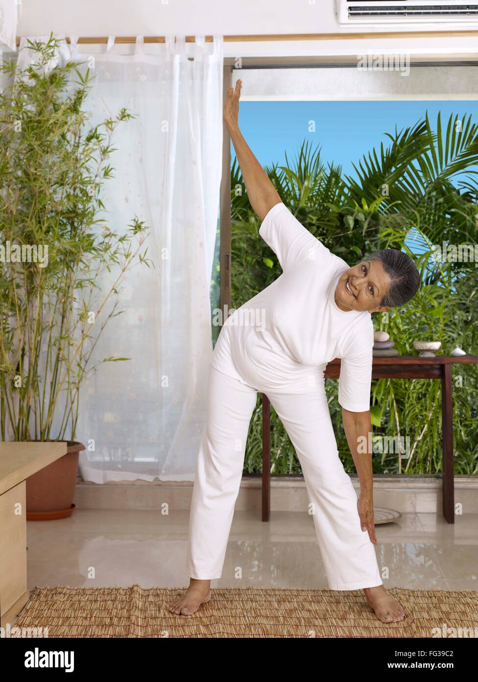 Old lady stretched one hand above and another hand below doing exercise ...