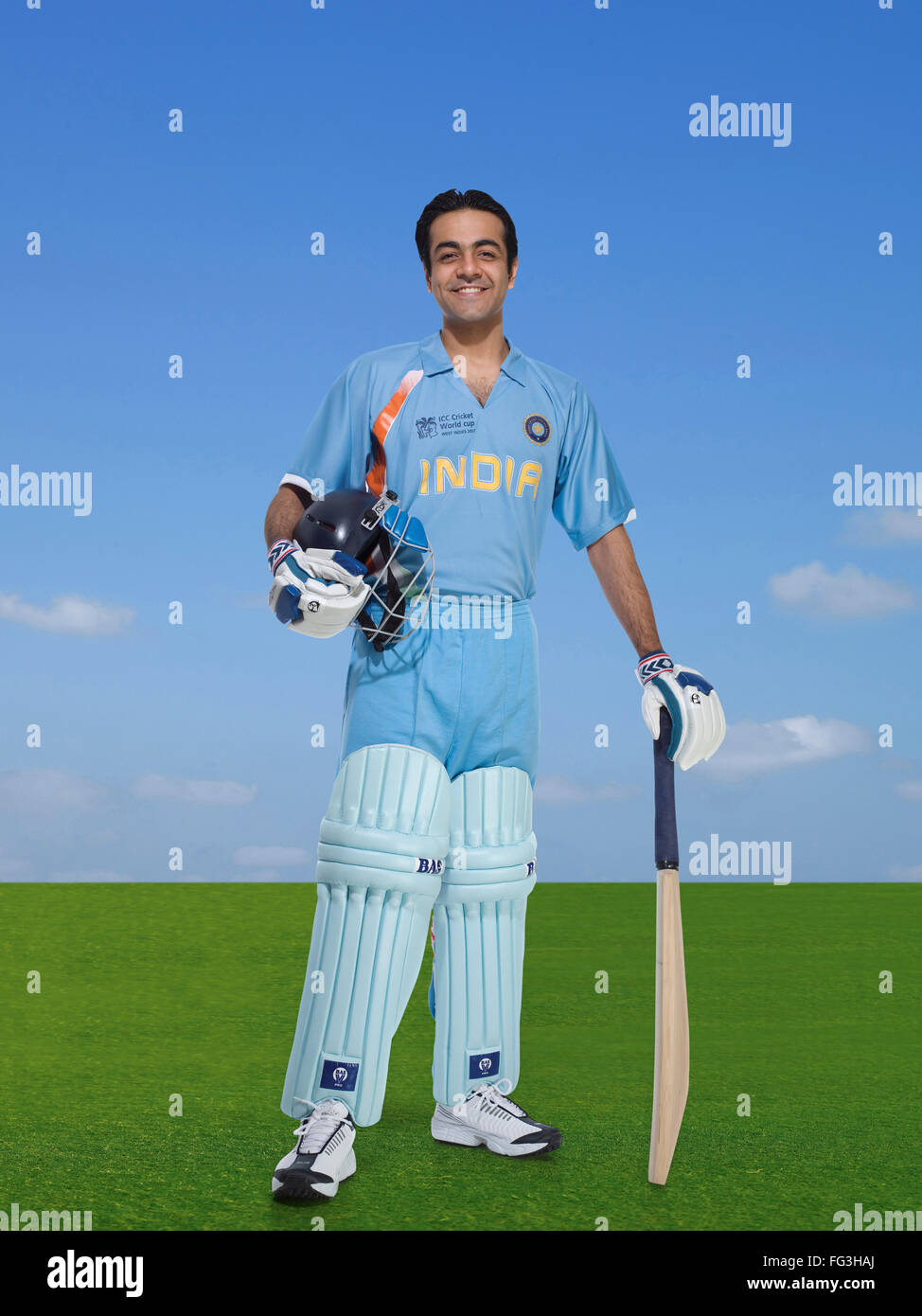 Batsman in helmet and pads holding bat standing on green grass MR Stock ...