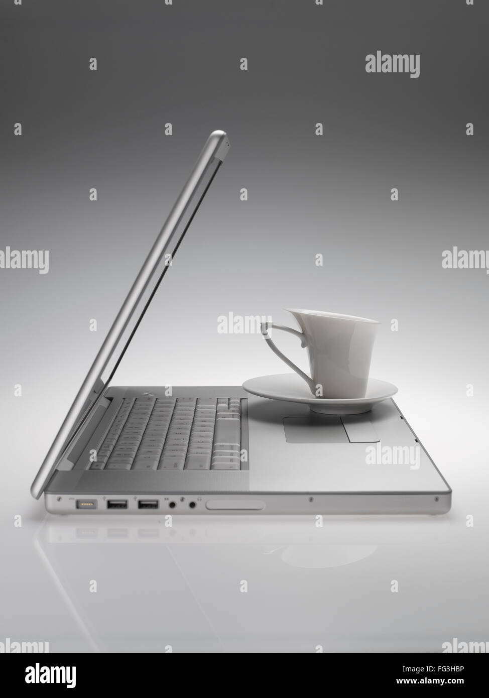 Mug with saucer on Macintosh laptop on white gray background Stock ...
