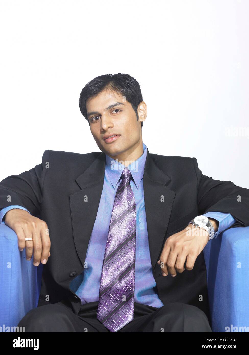 South Asian Indian executive man sitting on blue sofa MR Stock Photo ...