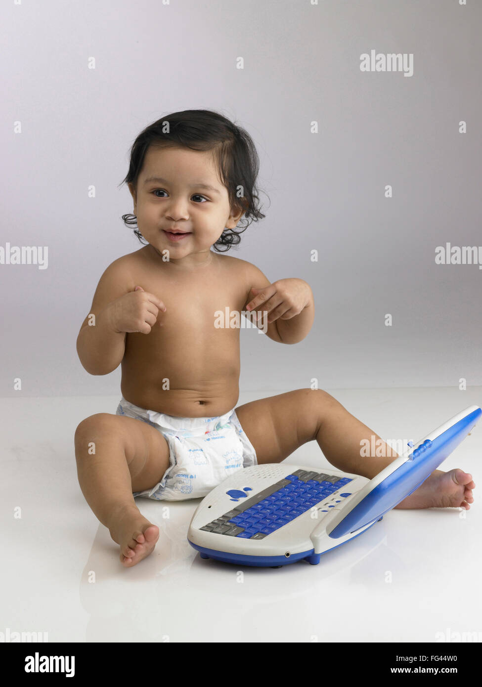 Indian baby girl wearing diaper playing with toy laptop MR#702O Stock ...