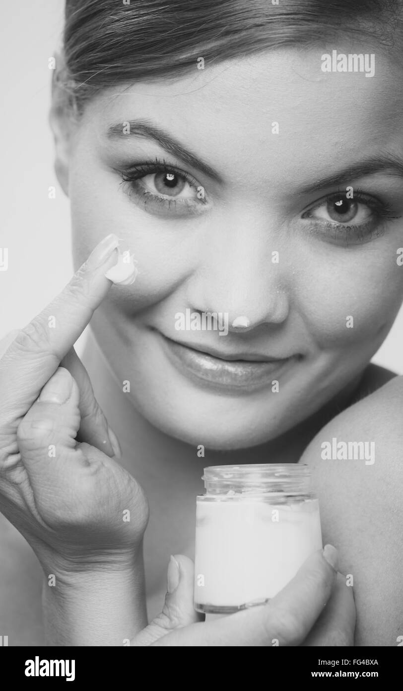 Woman applying moisturizing cream on her face. Female taking care of ...