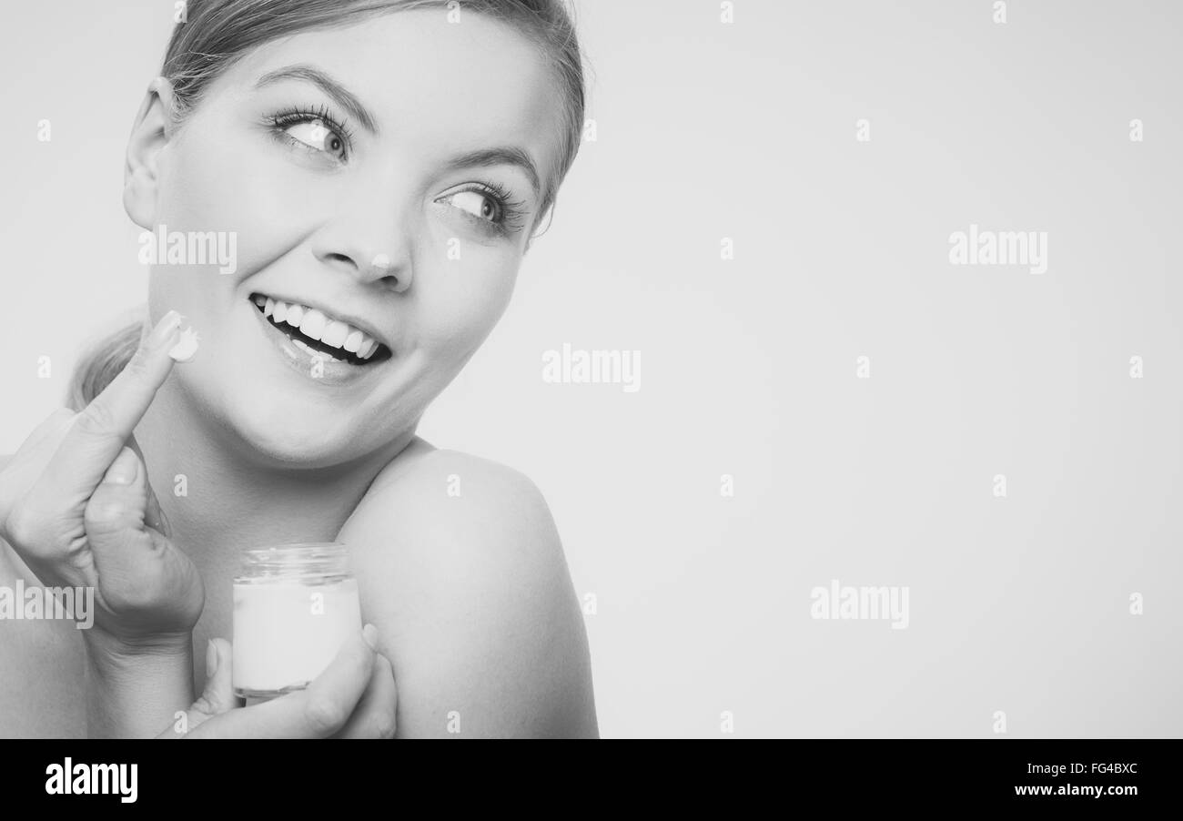 Woman applying moisturizing cream on her face. Female taking care of ...