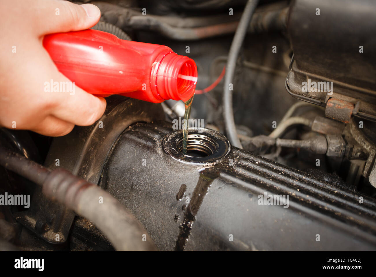 Car servicing mechanic pouring oil to engine. Closeup of fresh oil ...
