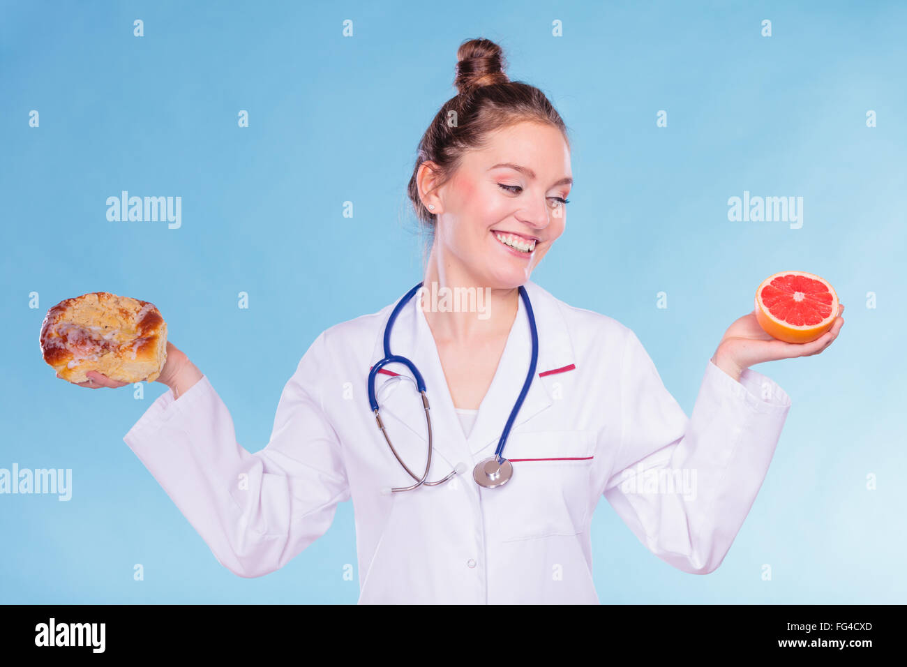 Happy dietitian nutritionist with sweet roll bun and grapefruit. Woman ...