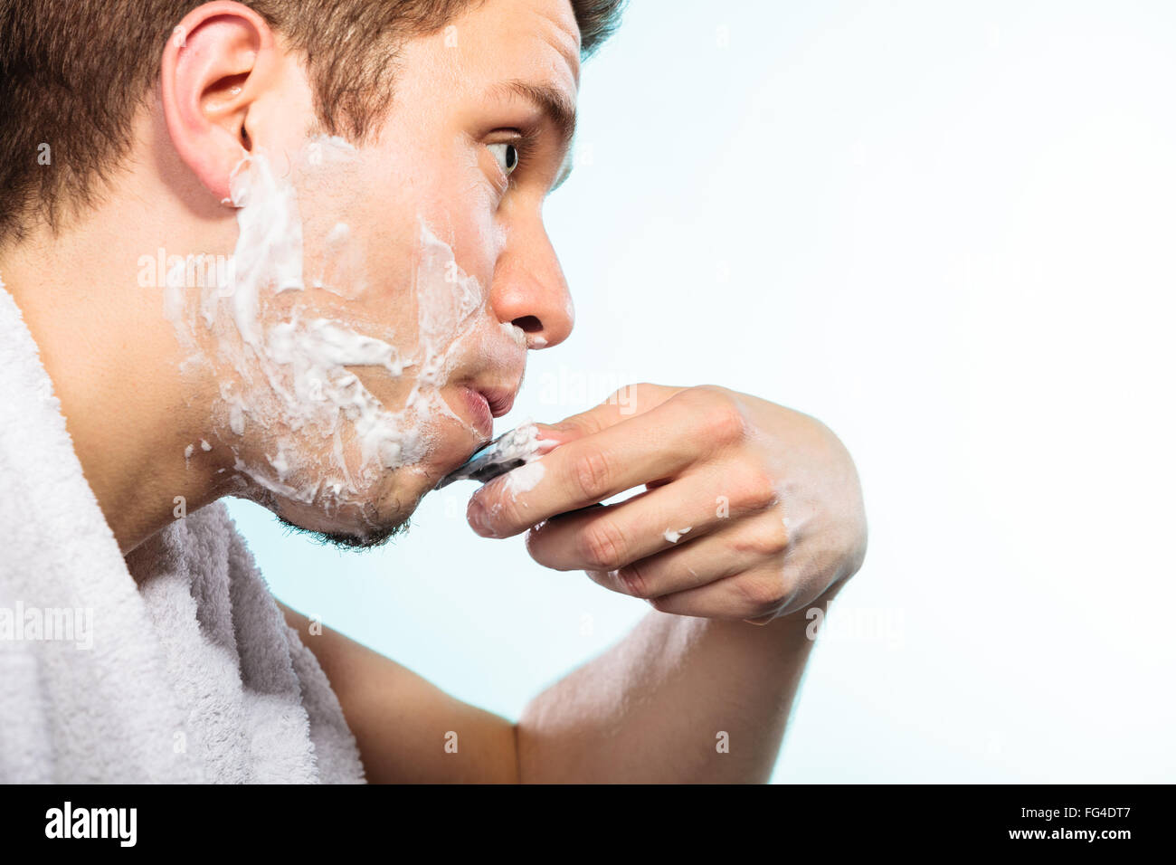 Man shaving using razor with cream foam. Handsome guy removing face beard hair. Skin care and ...