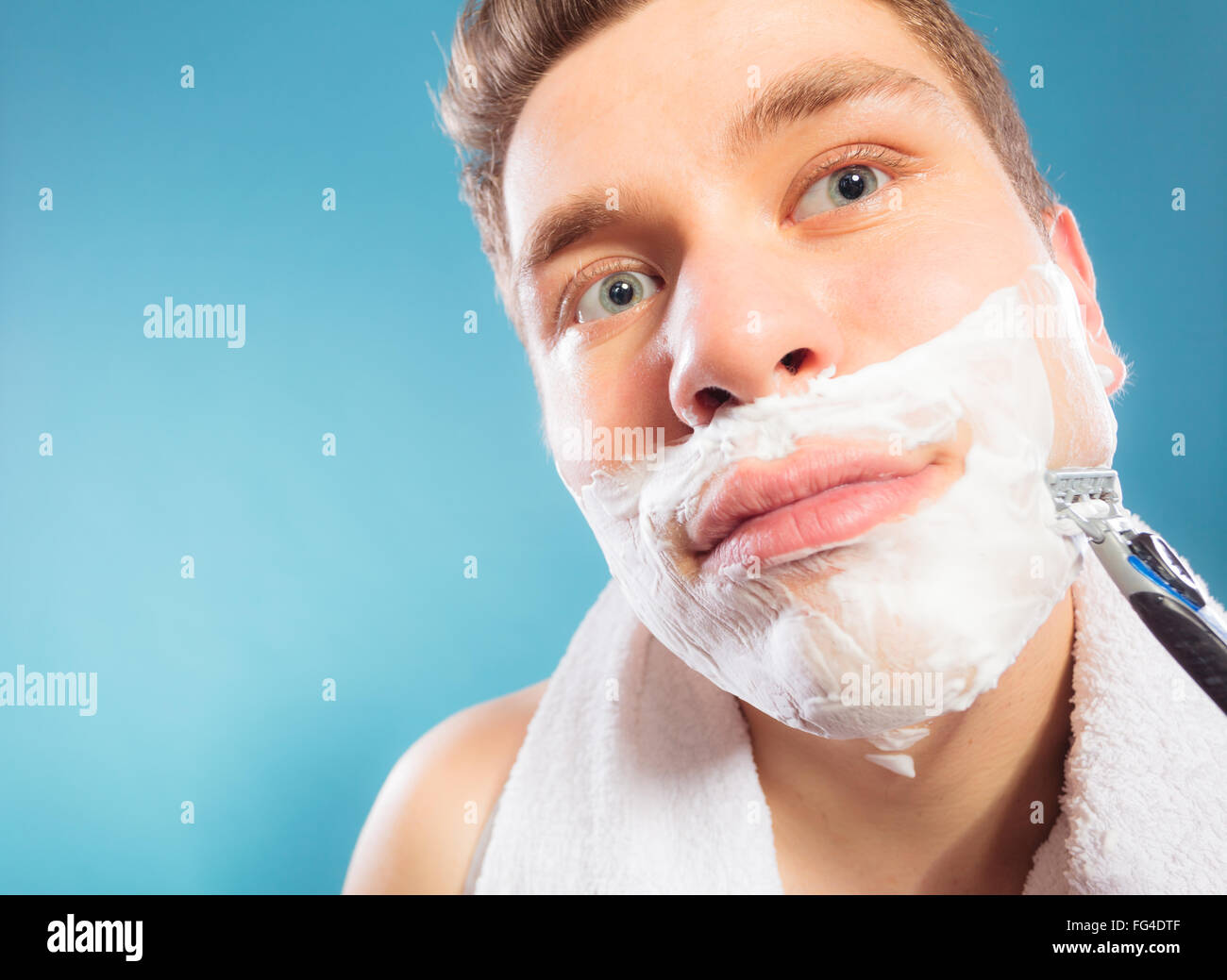 Man shaving using razor with cream foam. Handsome guy removing face beard hair. Skin care and ...