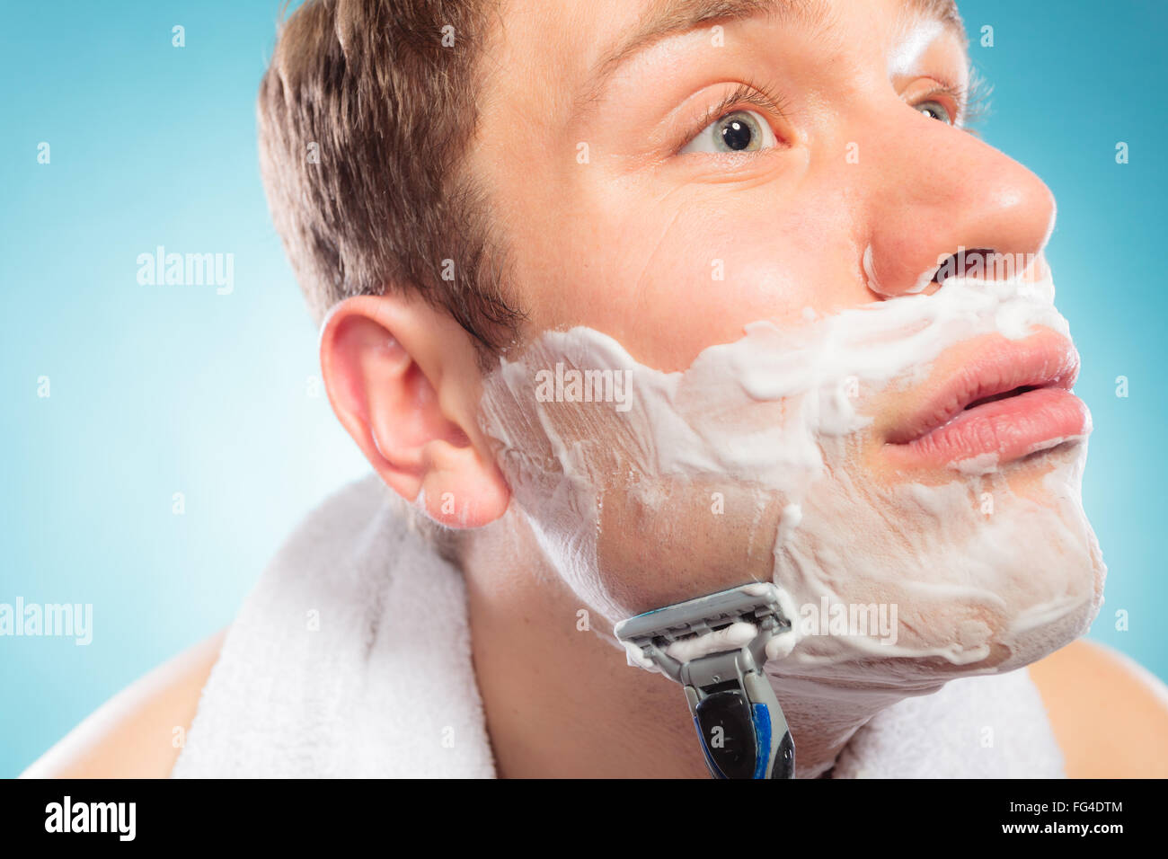 Man shaving using razor with cream foam. Handsome guy removing face beard hair. Skin care and ...