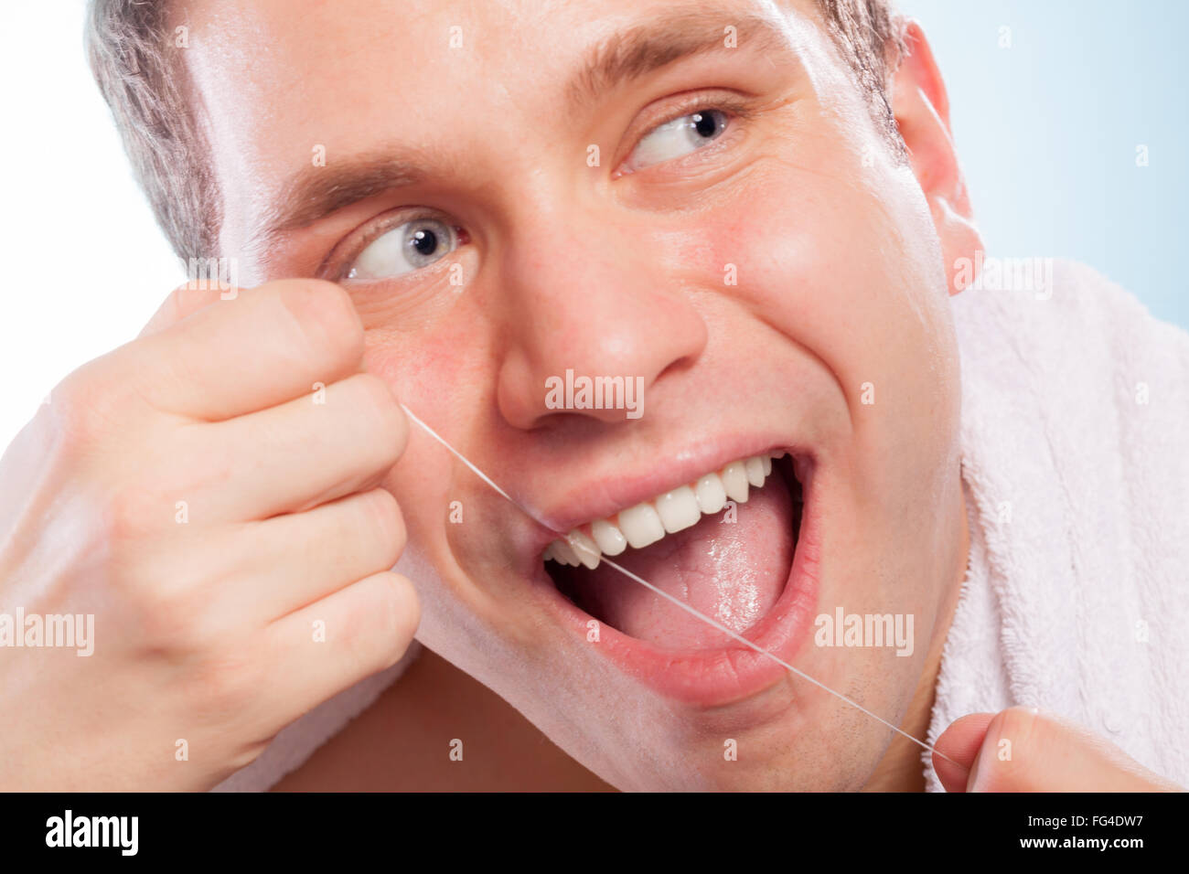 Daily health care. Young man cleaning flossing his white teeth with ...
