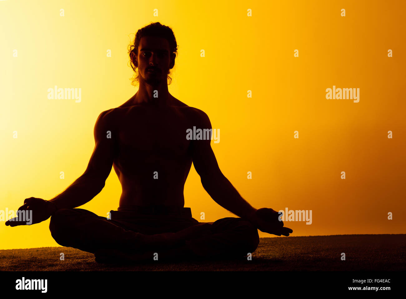 The man practicing yoga in the sunset light Stock Photo - Alamy